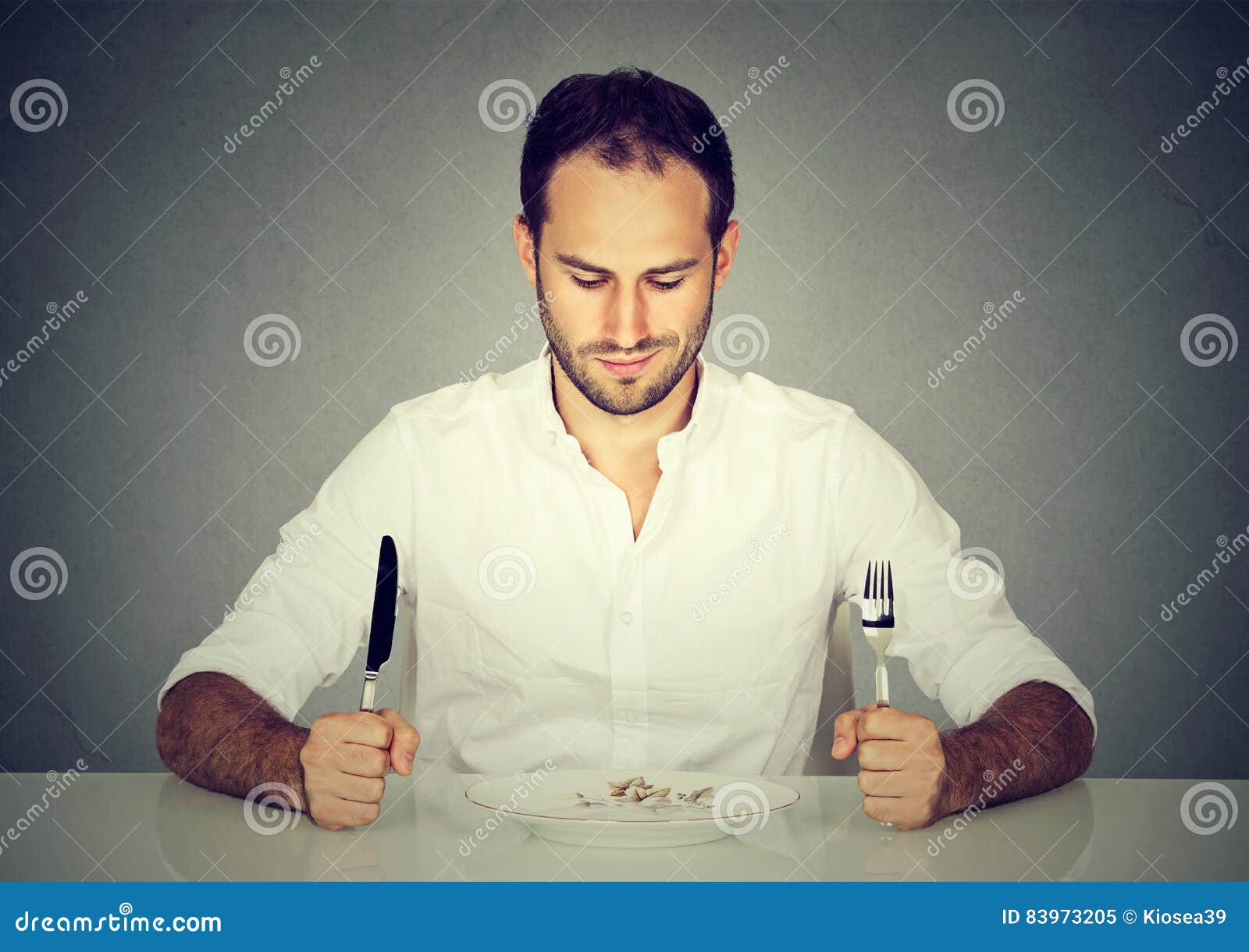 Man with Fork and Knife Sitting at Table Looking at Empty Plate Stock ...