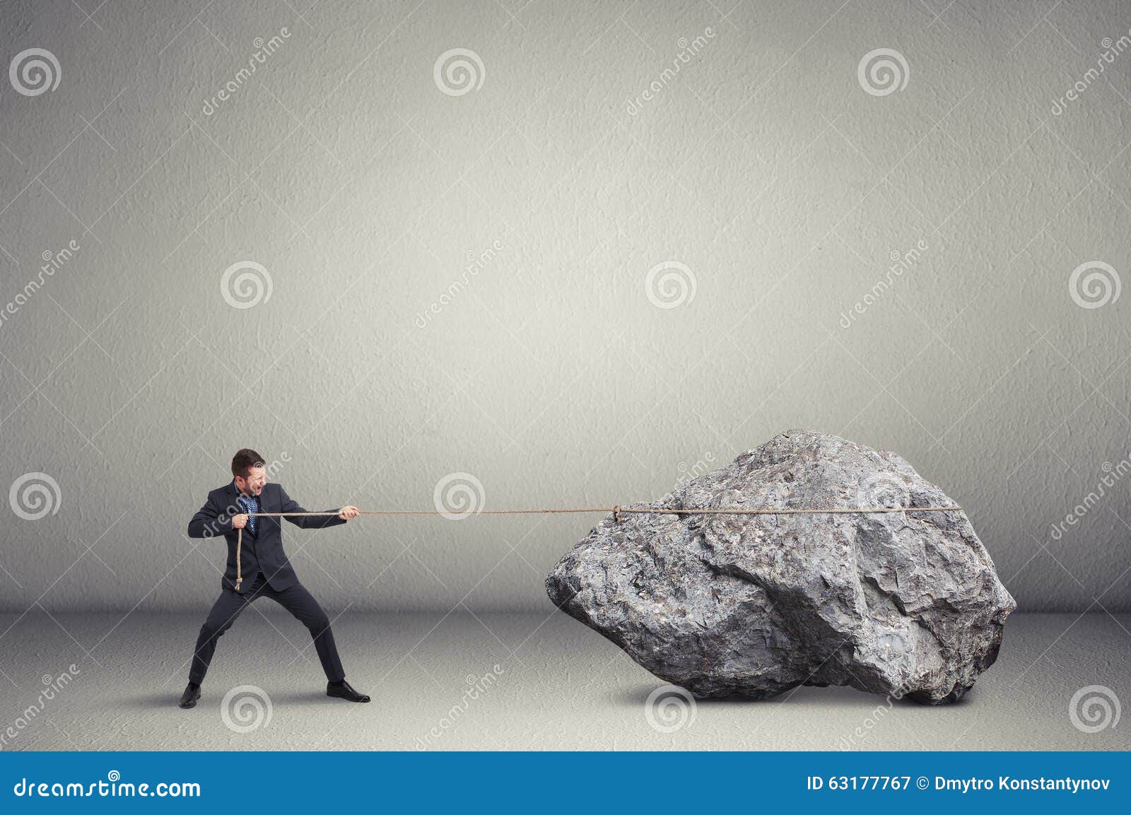 Man in Formal Wear Pulling the Big Stone Over Light Grey Background ...
