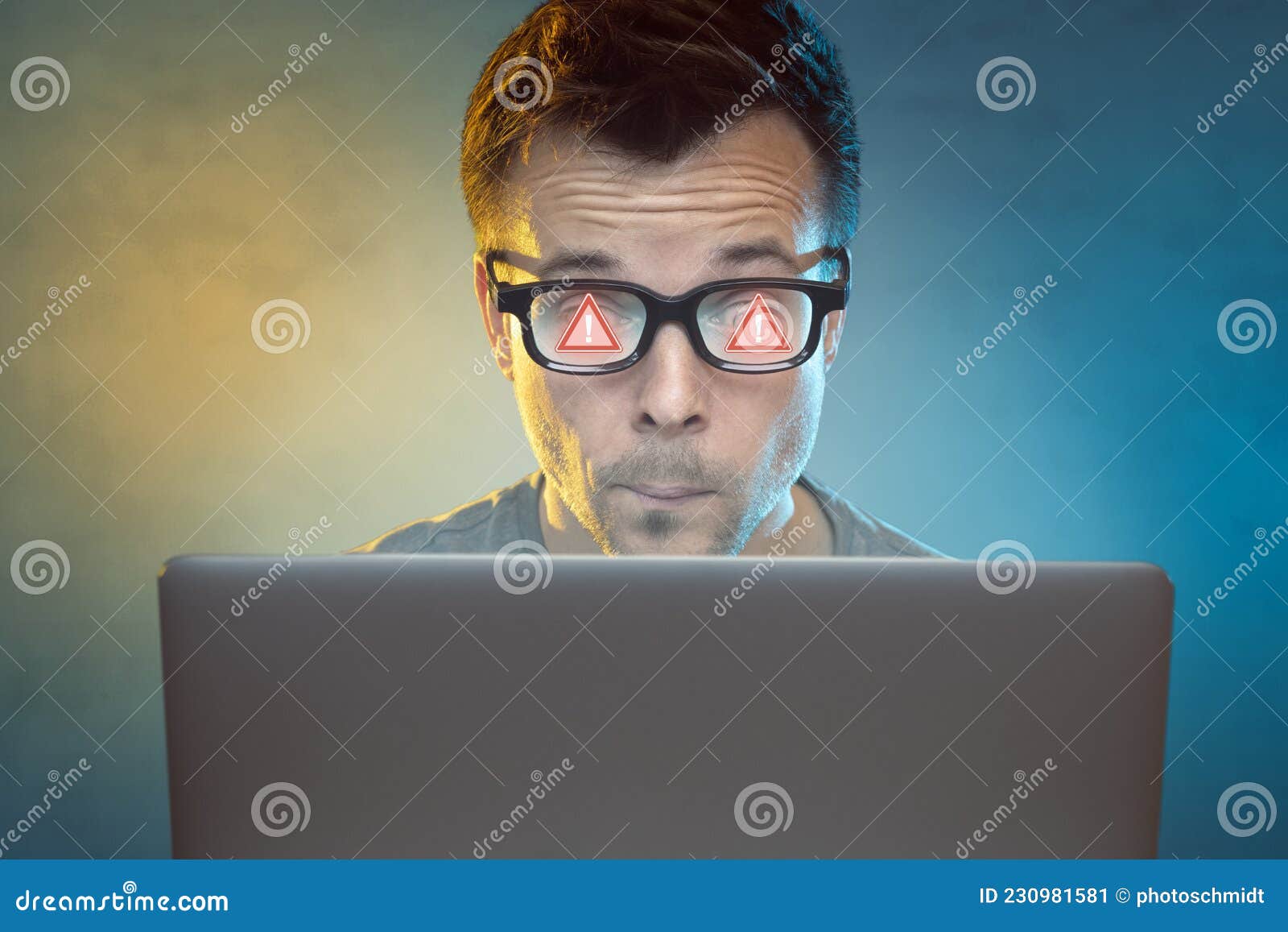 Man in Front of a Computer with an Alert Sign Reflecting in His Glasses ...
