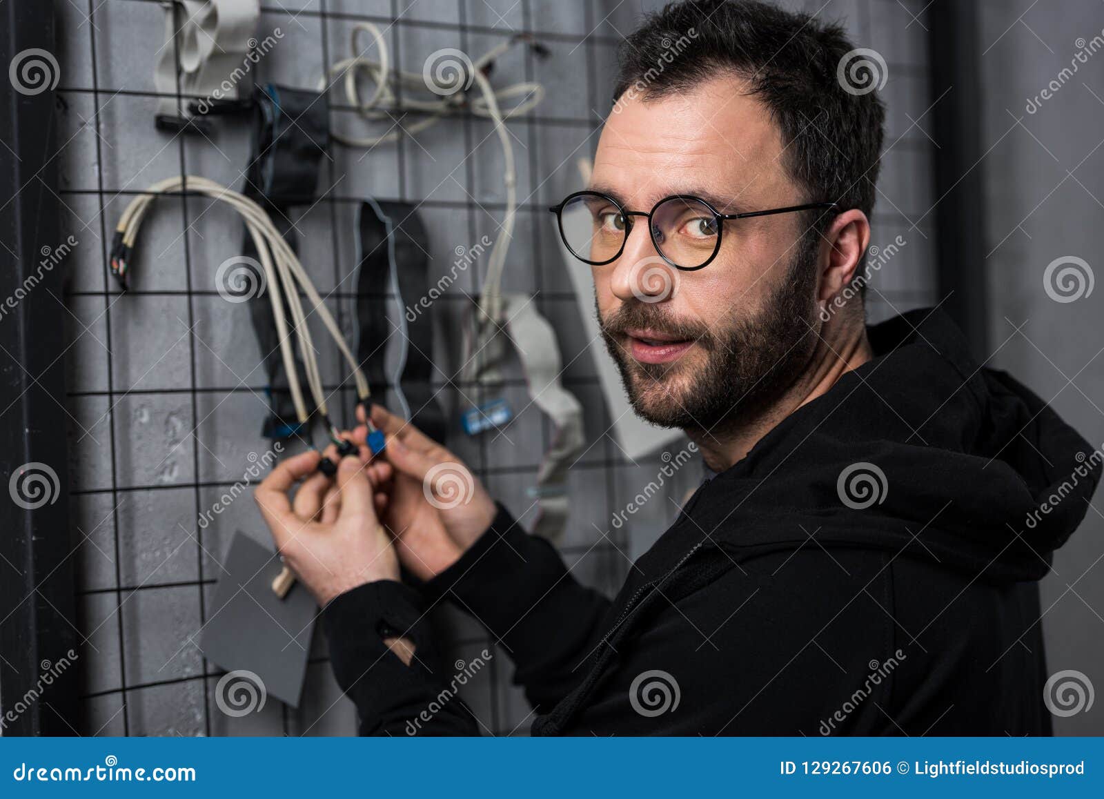 Man in Glasses Looking at Camera while Holding Wires Against Stock ...