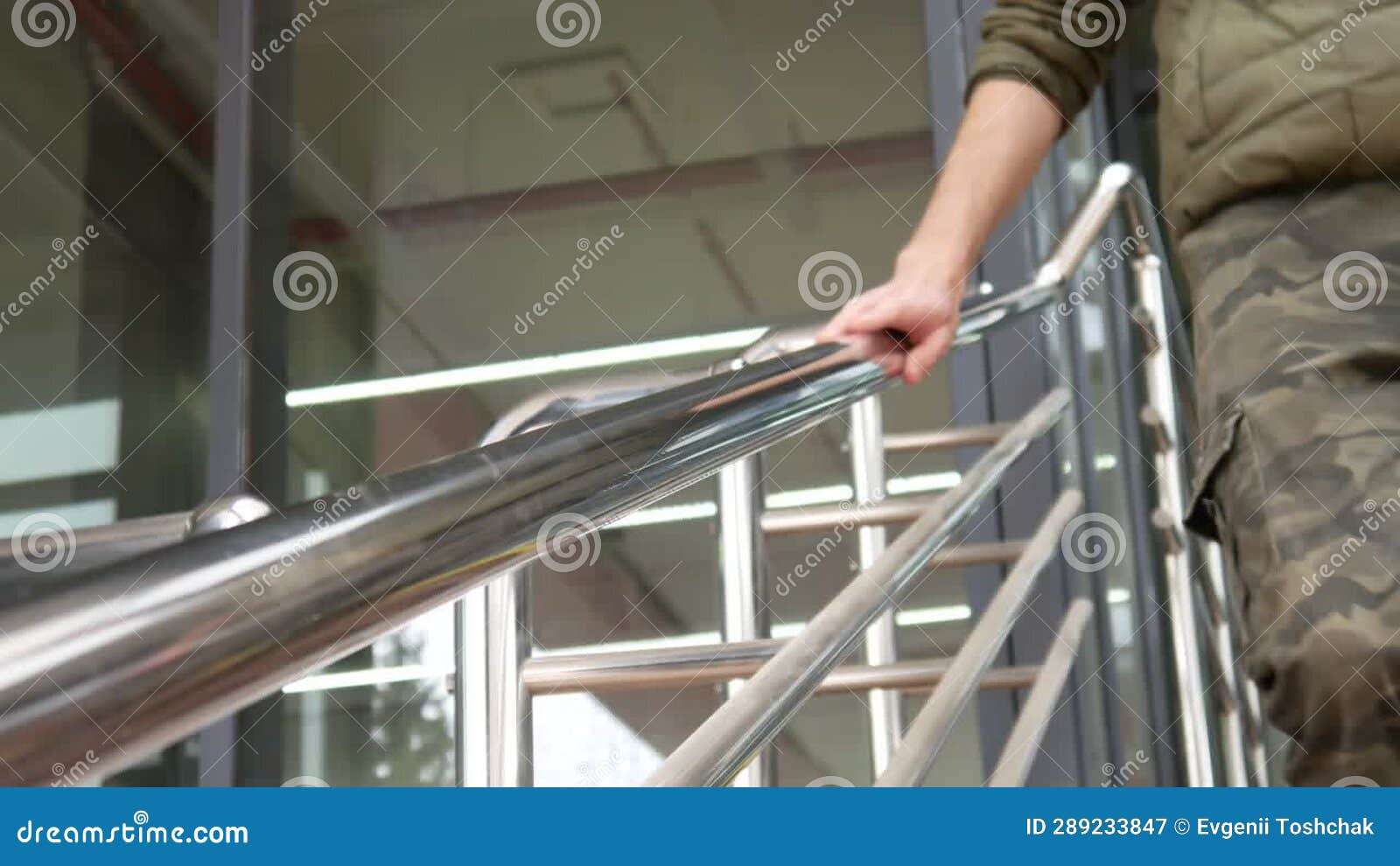 Close-up of a Handrail and a Man Going Down the Stairs Holding on To it ...