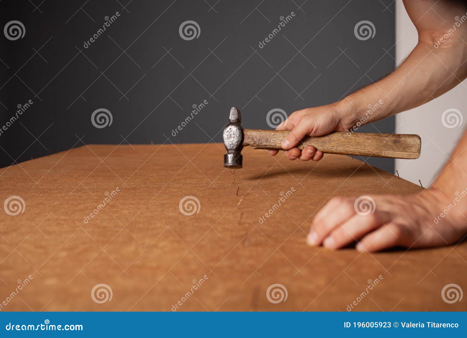 A Man Hammers Nails into a Cupboard. the Back Wall of the Cupboard is ...