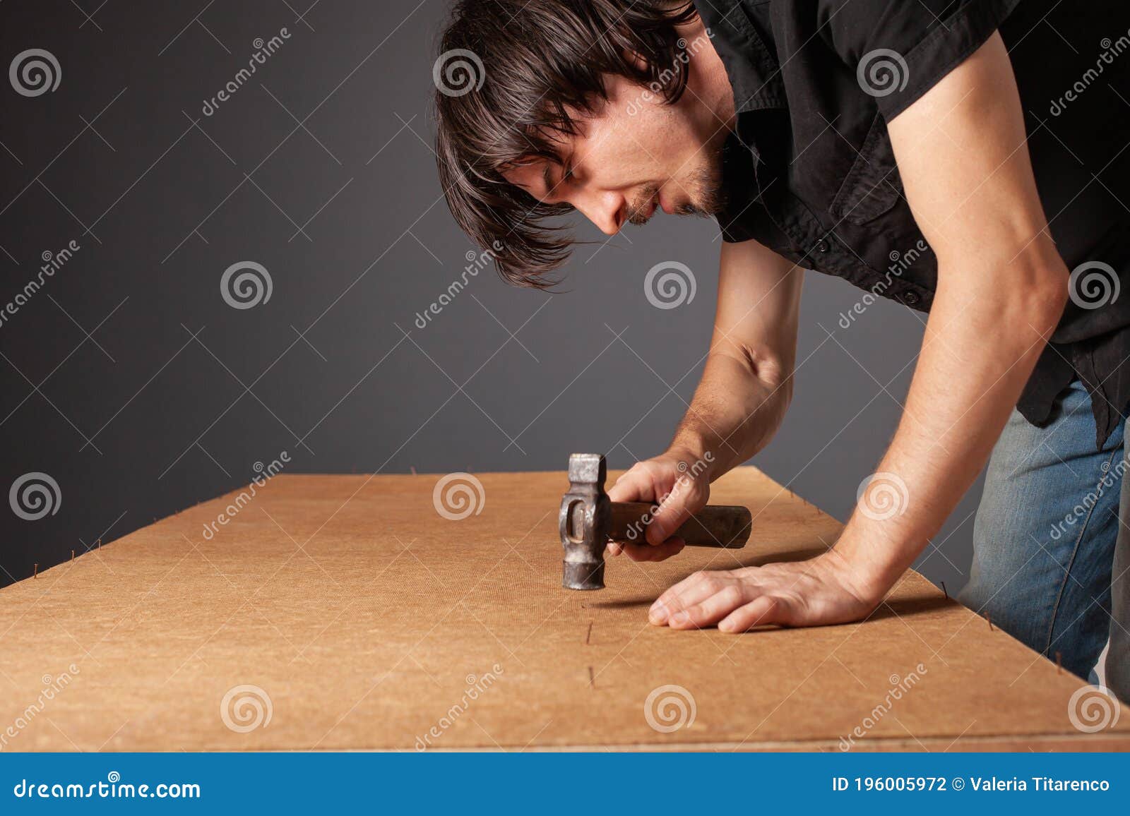 A Man Hammers Nails into a Cupboard. the Back Wall of the Cupboard is ...