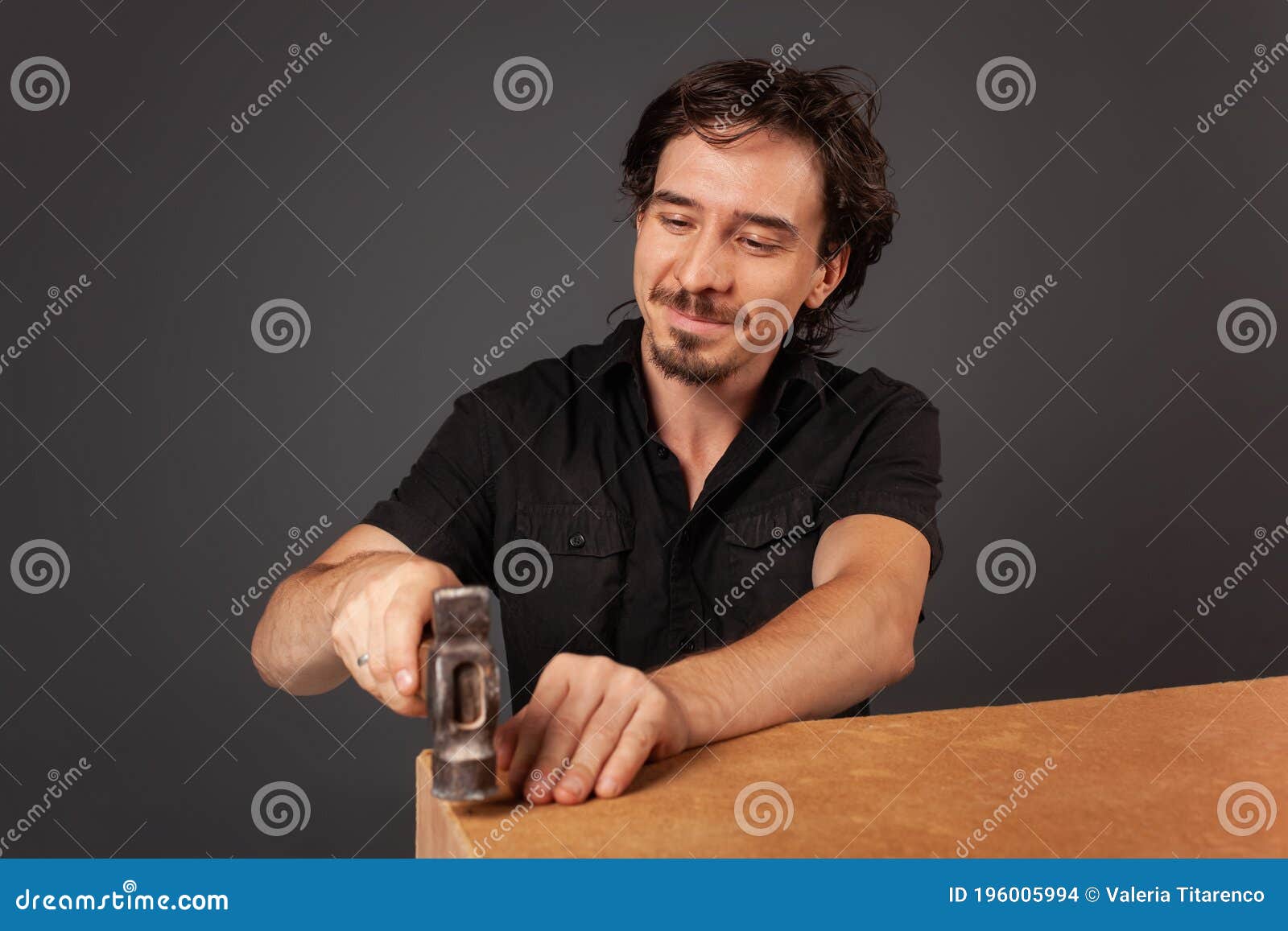 A Man Hammers Nails into a Cupboard. the Back Wall of the Cupboard is ...