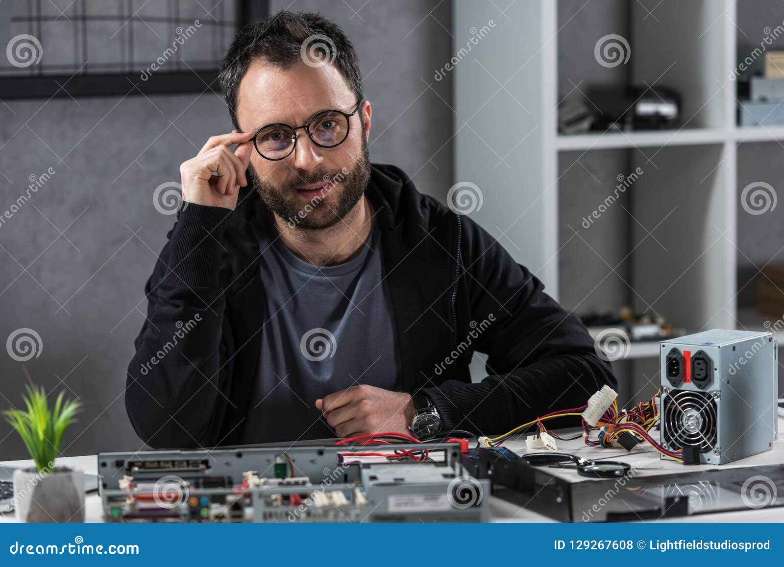 Man with Hand on Glasses Looking at Camera Against Computer Details ...