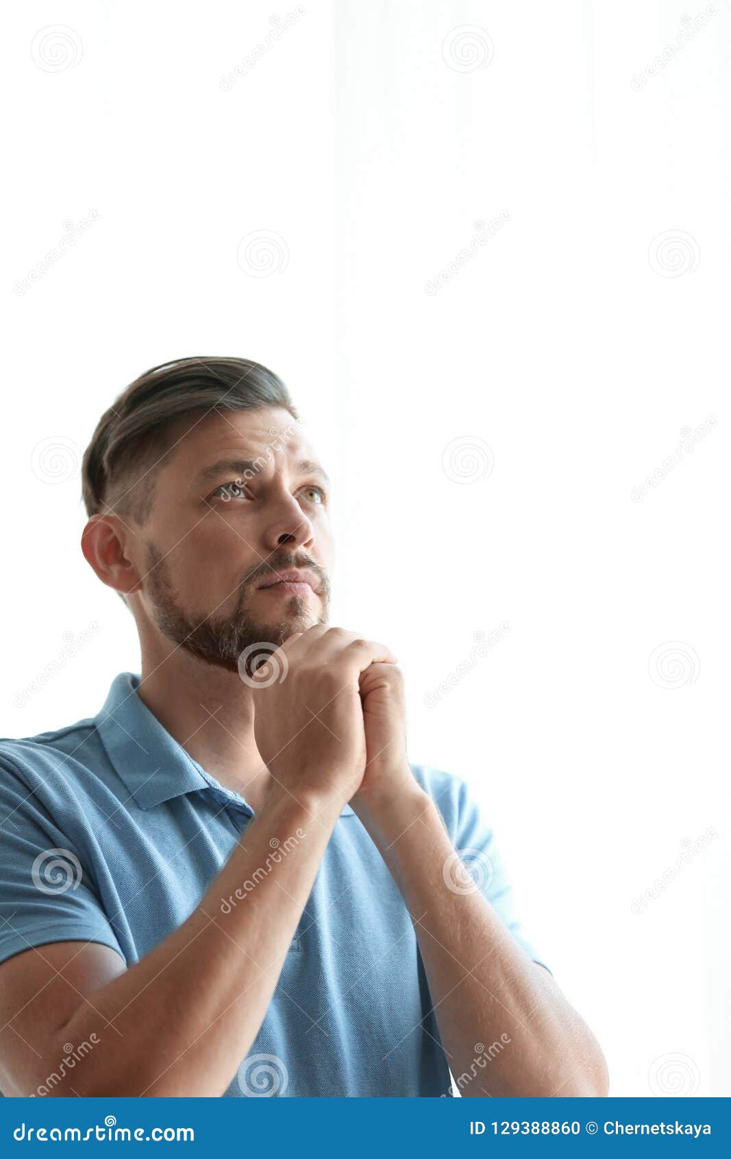 Man With Hands Clasped Together For Prayer On Light Background Stock