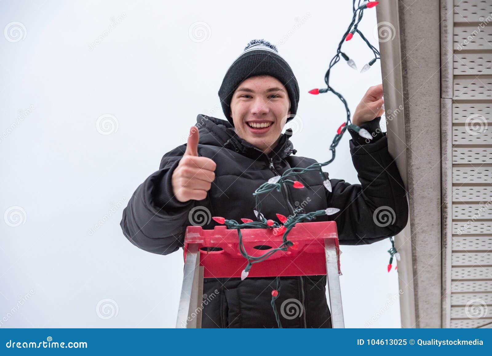 Man Hanging Christmas Lights Outdoors while on a Ladder. Stock Image ...