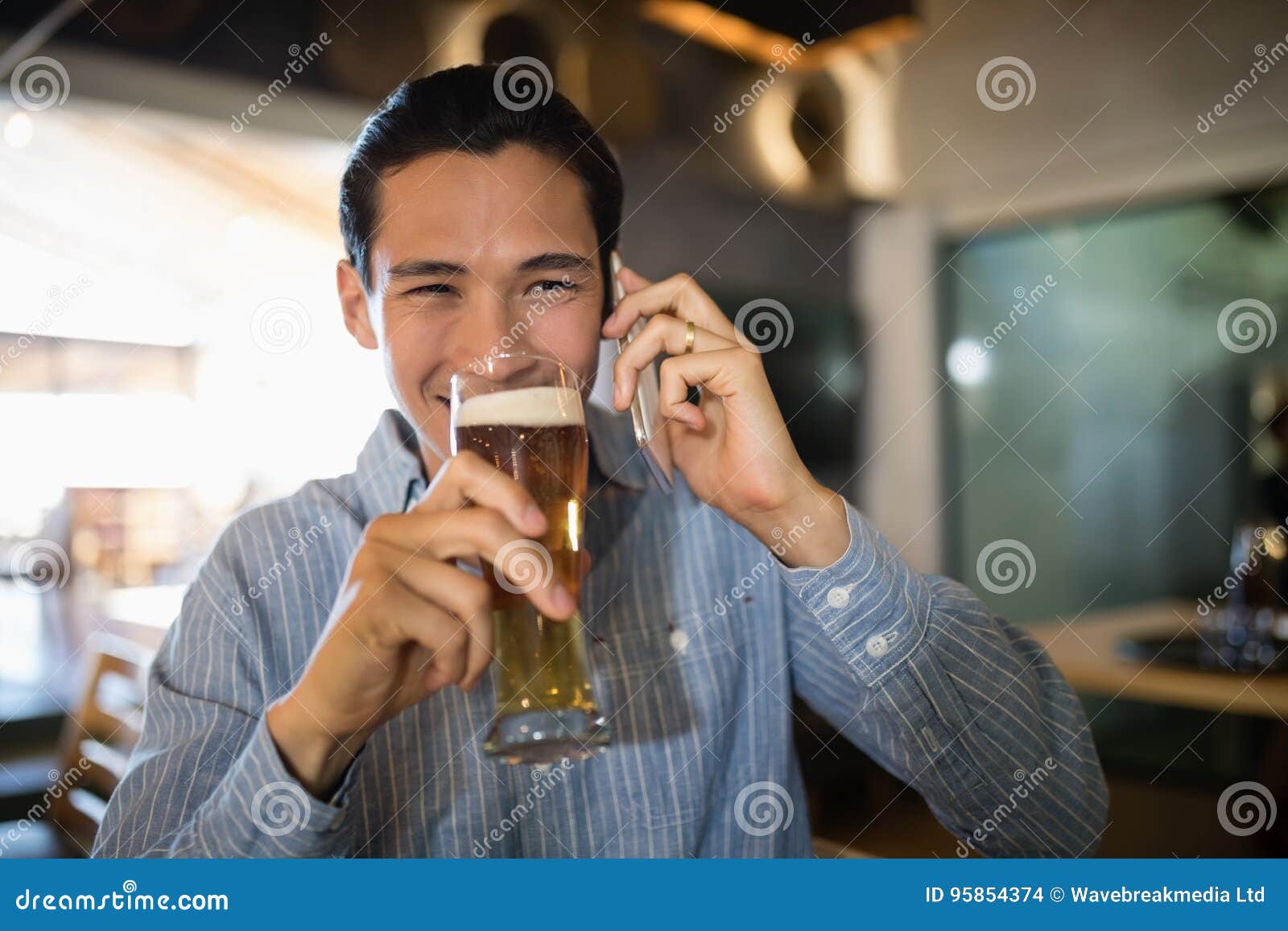 Man Having Beer while Talking on Mobile Phone Stock Photo - Image of ...