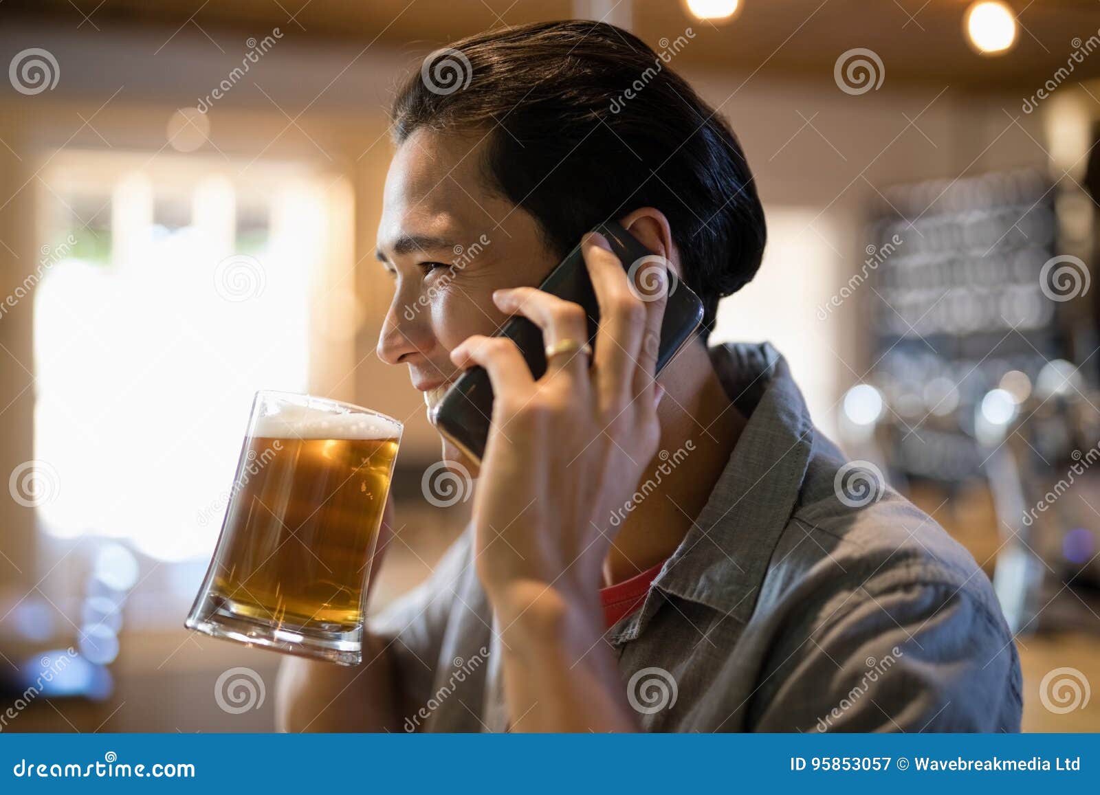 Man Having Beer while Talking on Mobile Phone in a Restaurant Stock ...