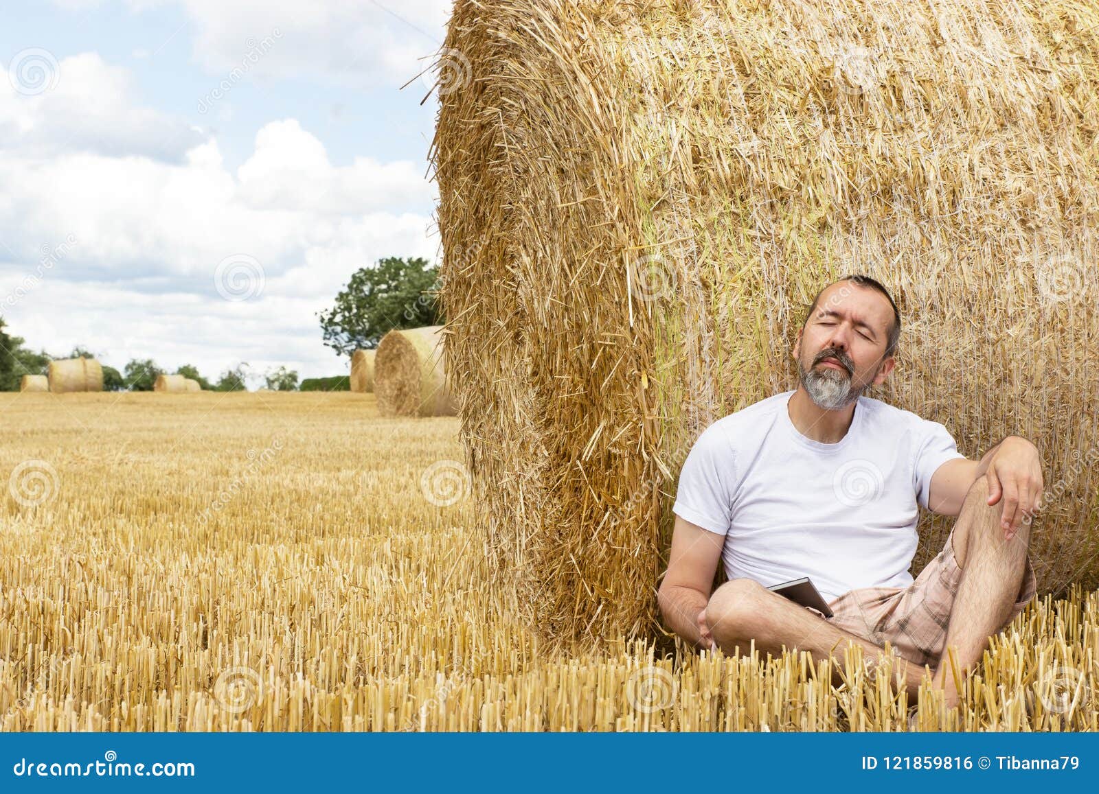 Man at a hay bale stock photo. Image of read, season - 121859816
