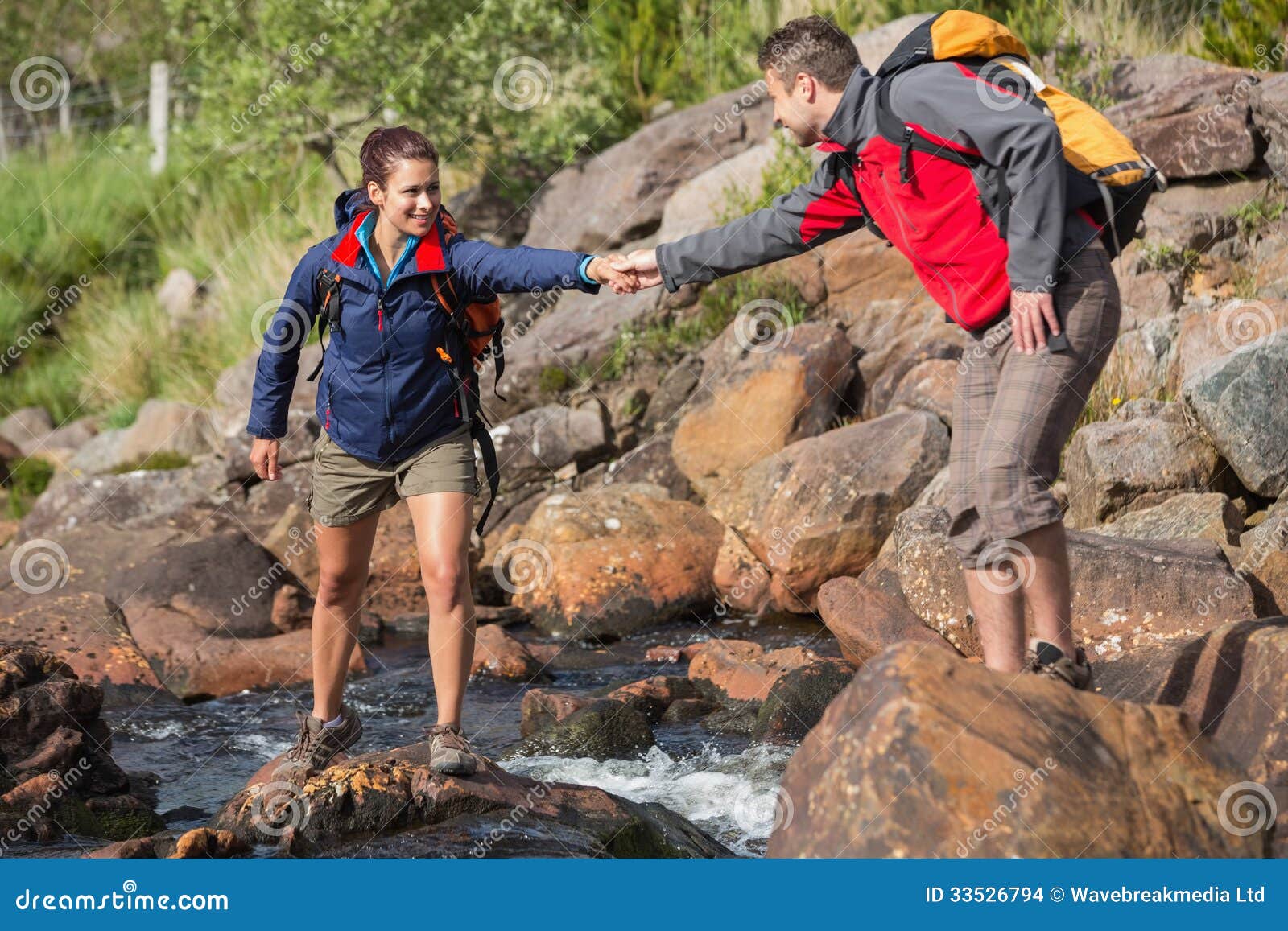 Man Helping His Smiling Girlfriend To Cross a River Stock Photo - Image ...