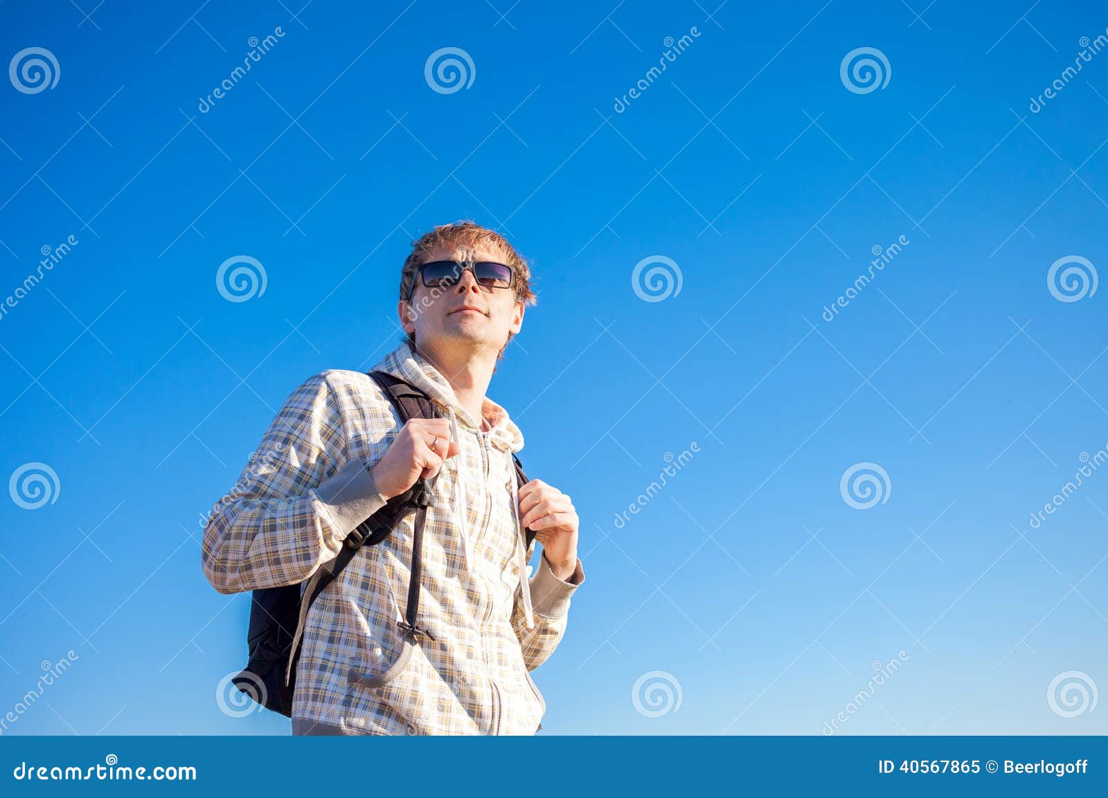Man Hiker Holding Backpack on a Sunny Day Against a Blue Sky Stock ...