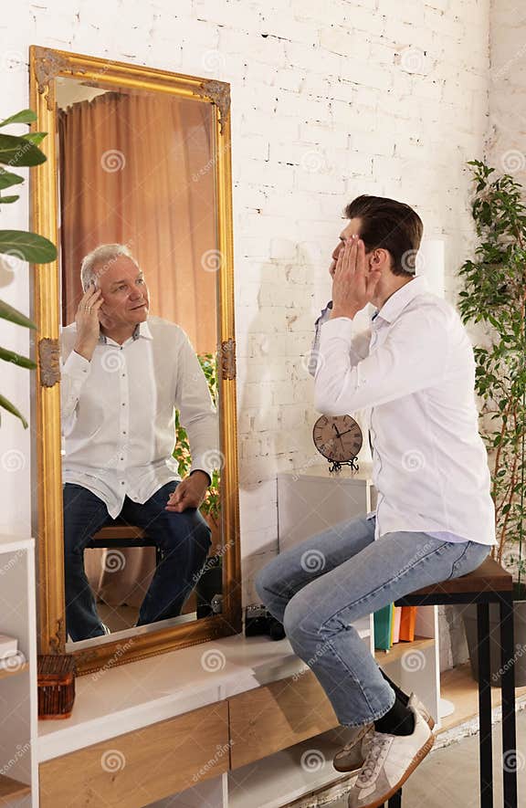 Man and His Elder Self Reflected in Mirror, Both Touching Their Faces Looking at Age-old Changes ...