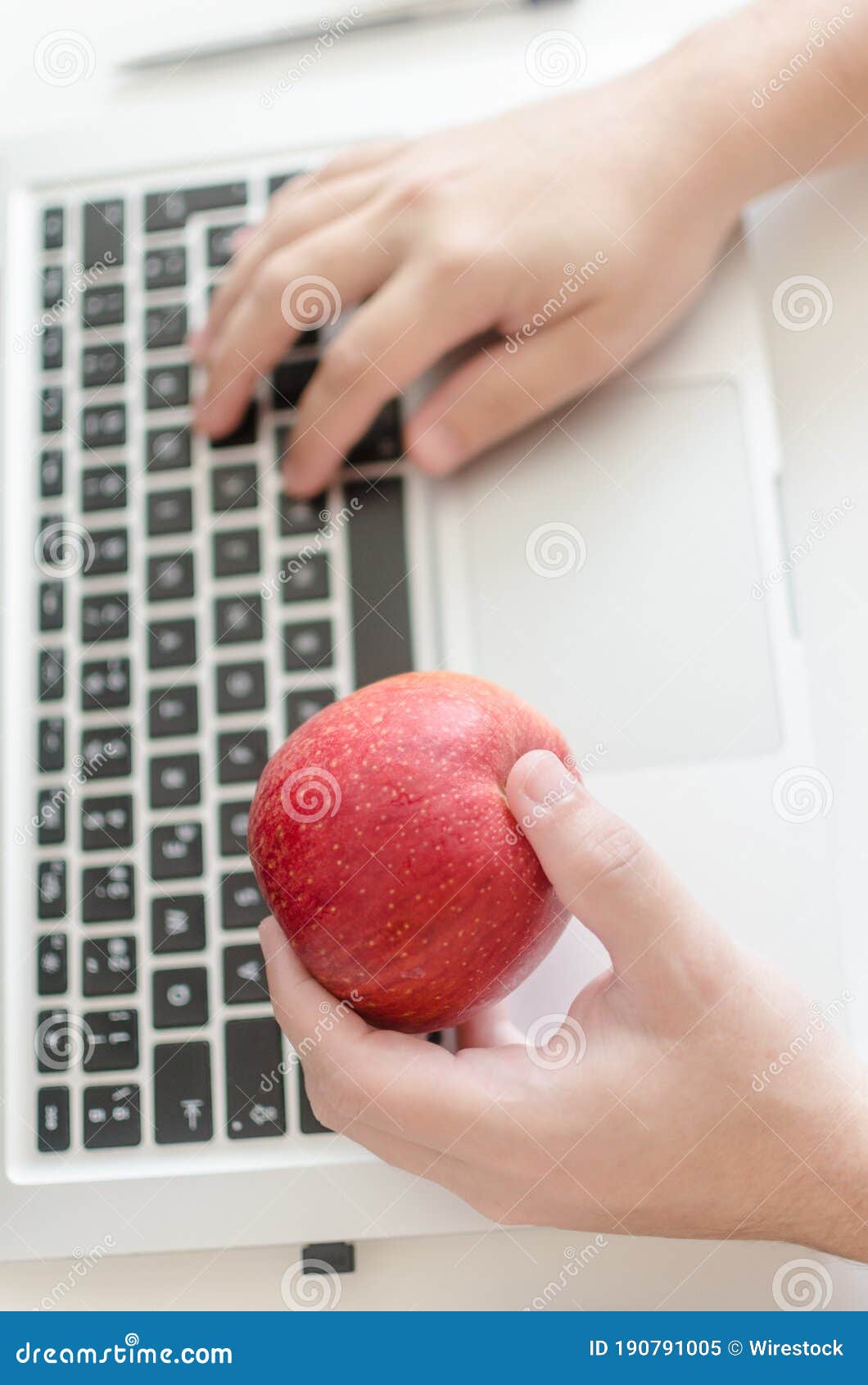 Man Holding an Apple while Typing on His Laptop Stock Image - Image of ...