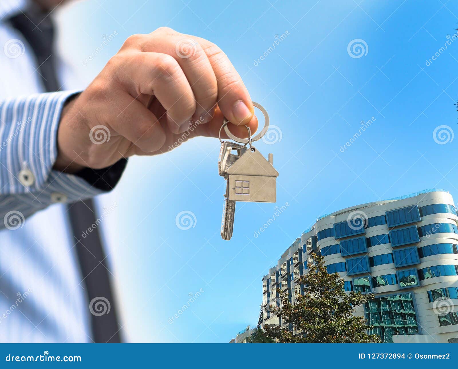 Man Holding a Home Key in His Hand and Residence Background Stock Photo ...