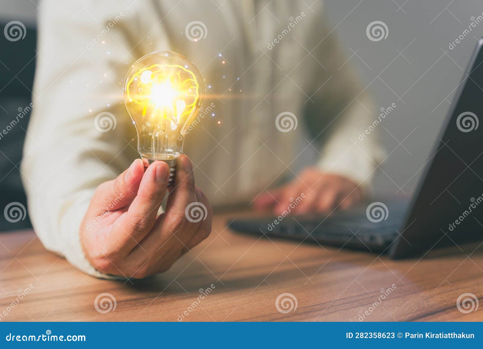 Man Holding a Light Bulb while Working on a Computer Laptop To Think ...