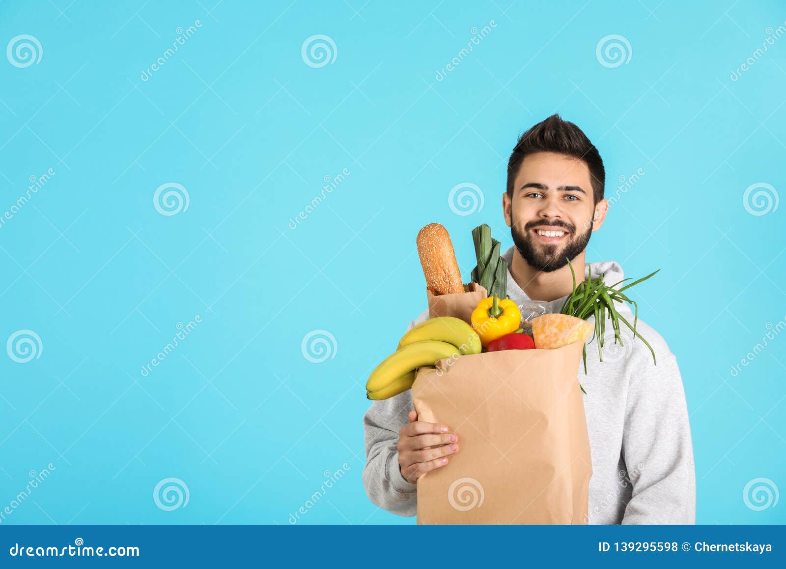 Man Holding Paper Bag with Fresh Products on Color Background, Space ... Man Holding Paper Bag with Fresh Products on Color Background, Space ...