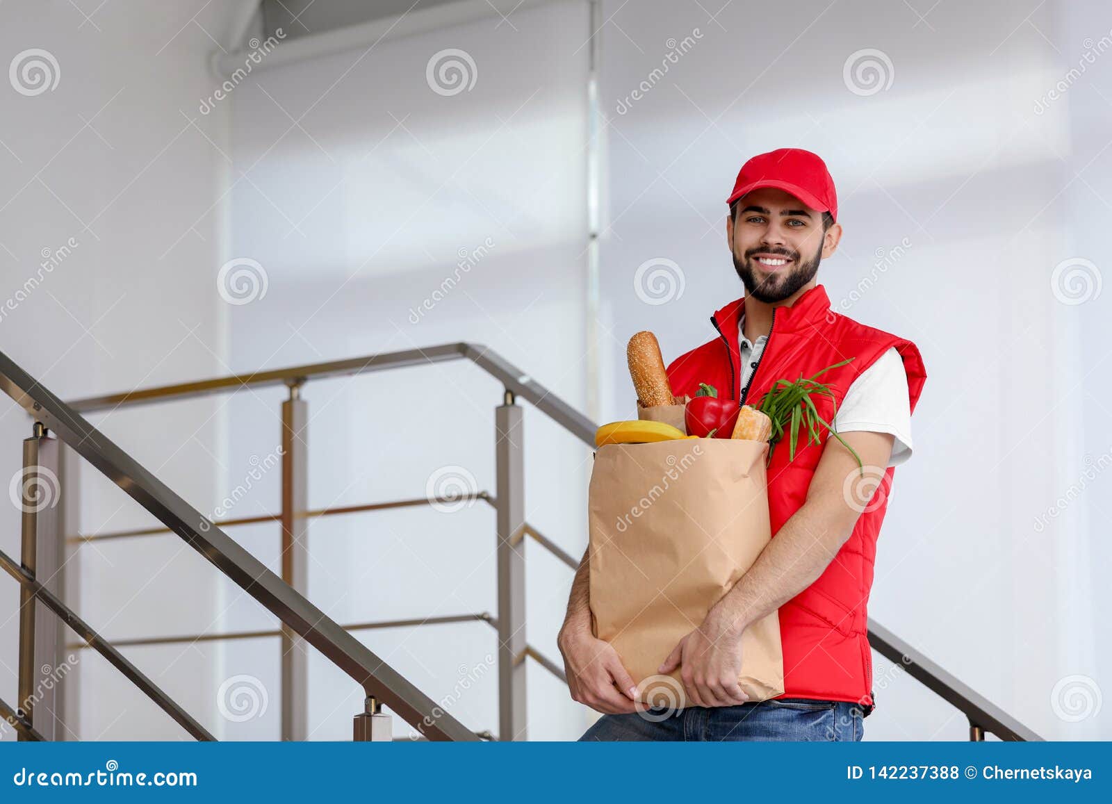 Man Holding Paper Bag with Fresh Products on Staircase, Space for Text ... Man Holding Paper Bag with Fresh Products on Staircase, Space for Text ...