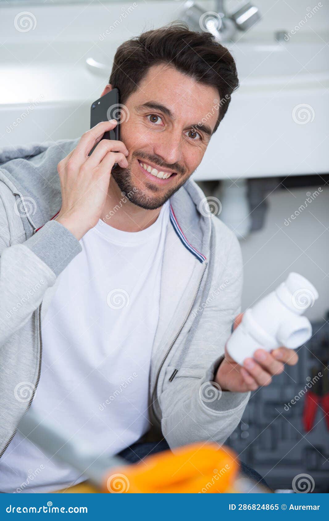 Man Holding Plumbing Fitting and Using Smartphone Stock Image - Image ...
