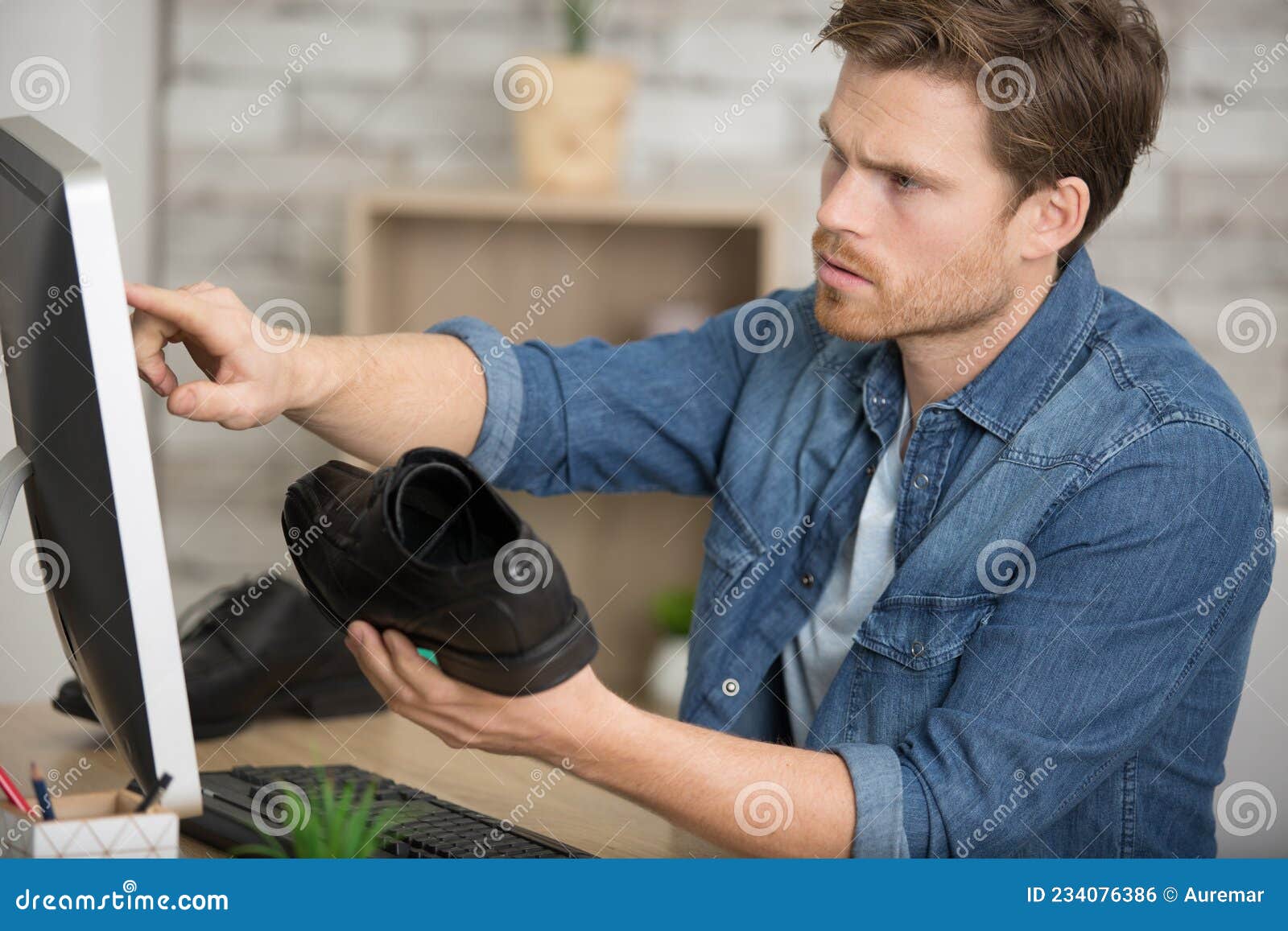 Man Holding Shoe and Reading Description on Computer Screen Stock Photo ...