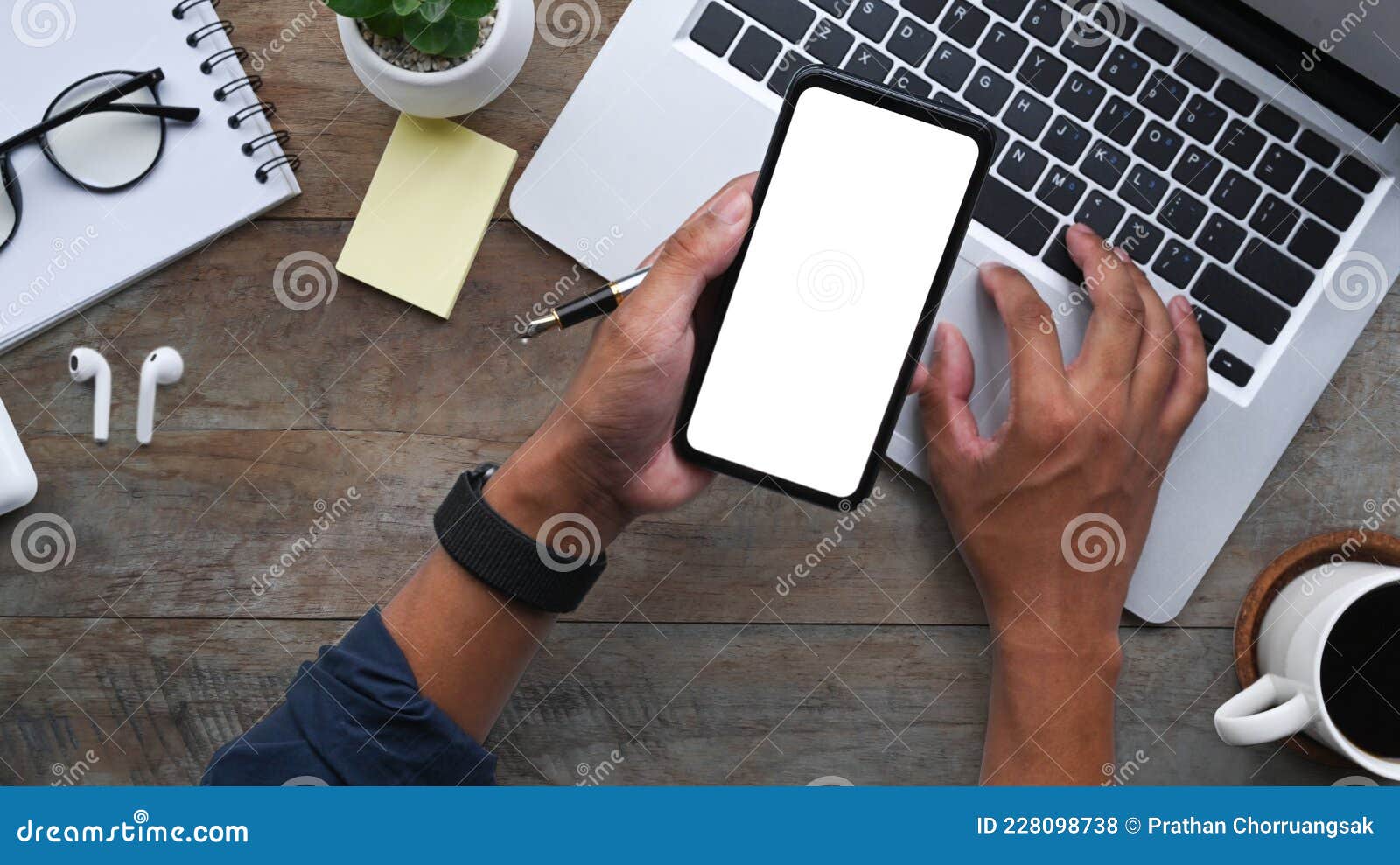 Man Holding Smart Phone and Working with Laptop Computer at Workspace ...