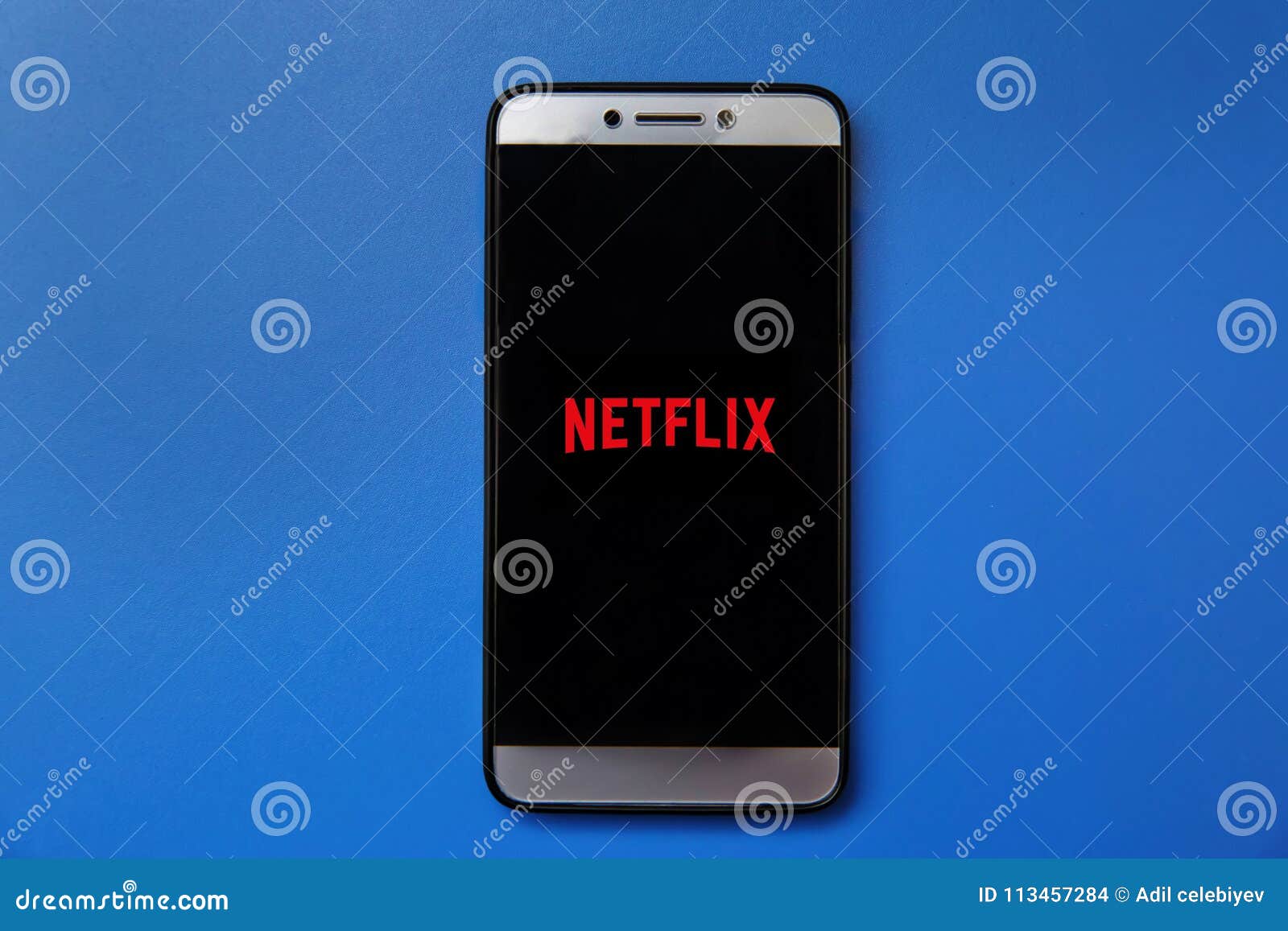 Netflix Logo on Smartphone Screen on Blue Background. Man Holding ...