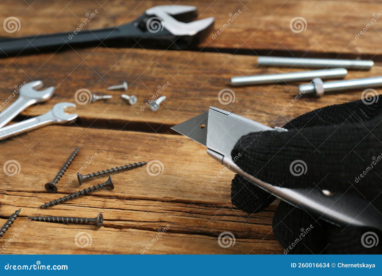 Man Holding Utility Knife and Different Tools on Wooden Table, Closeup ...