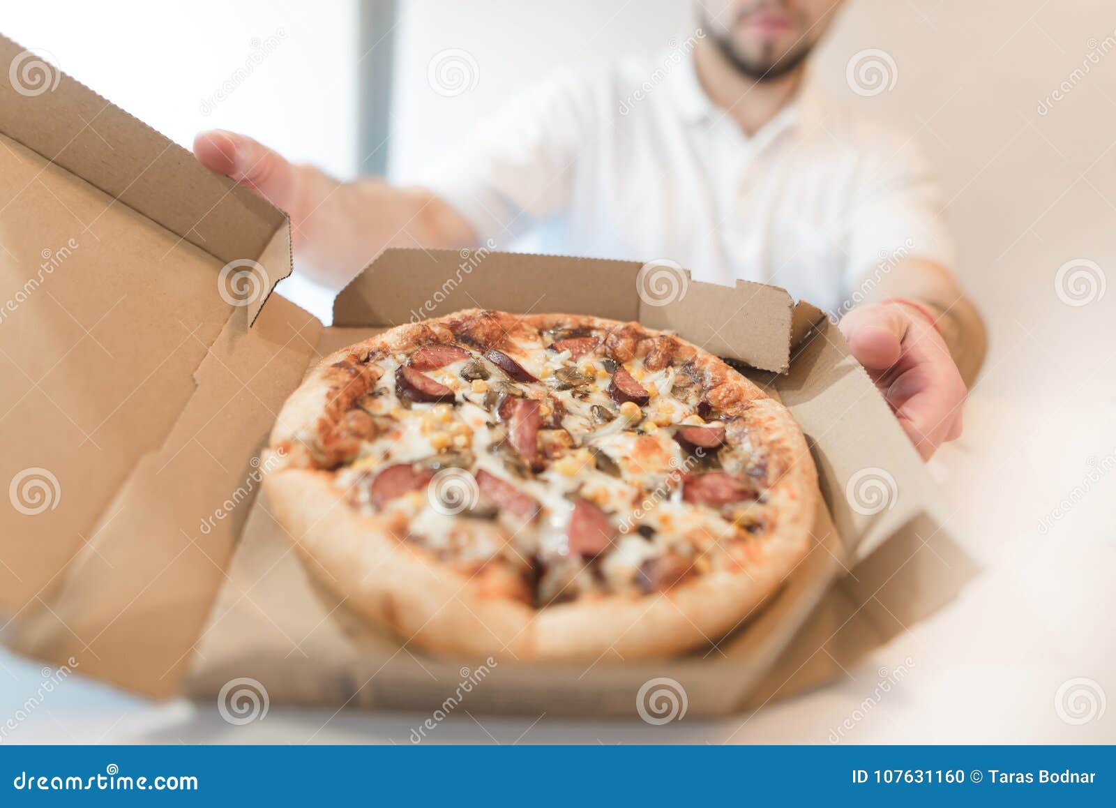 A Man Holds a Box of Appetizing Pizza in His Hands and Offers it To ... A Man Holds a Box of Appetizing Pizza in His Hands and Offers it To ...