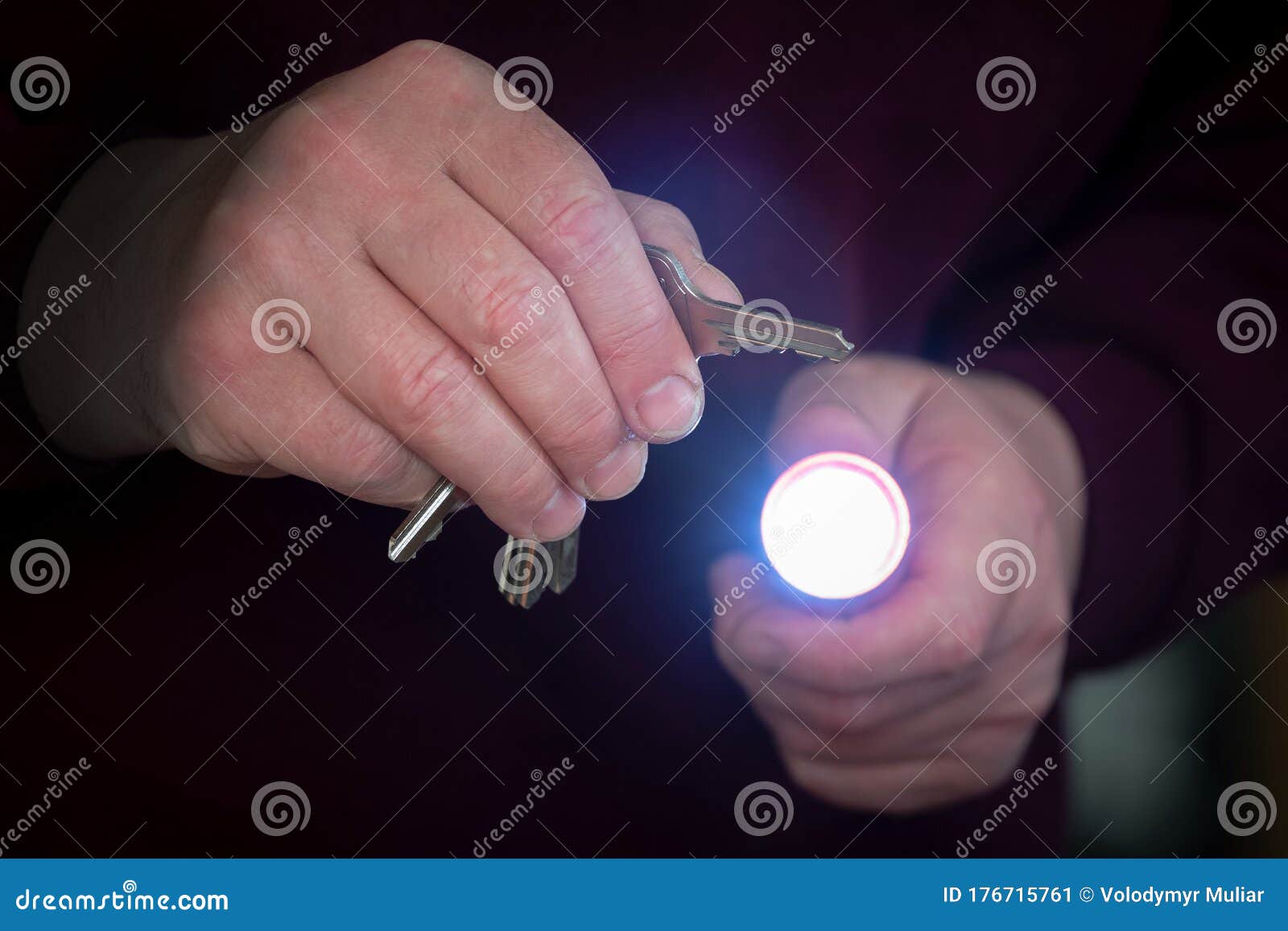 A Man Holds a Key and a Flashlight at Night and Shines a Flashlight ...