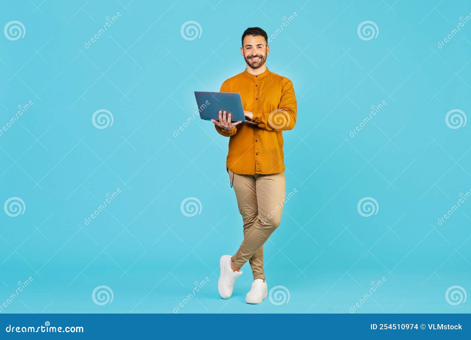 A Man Holds a Laptop in His Hands while Standing, Working on a PC ...
