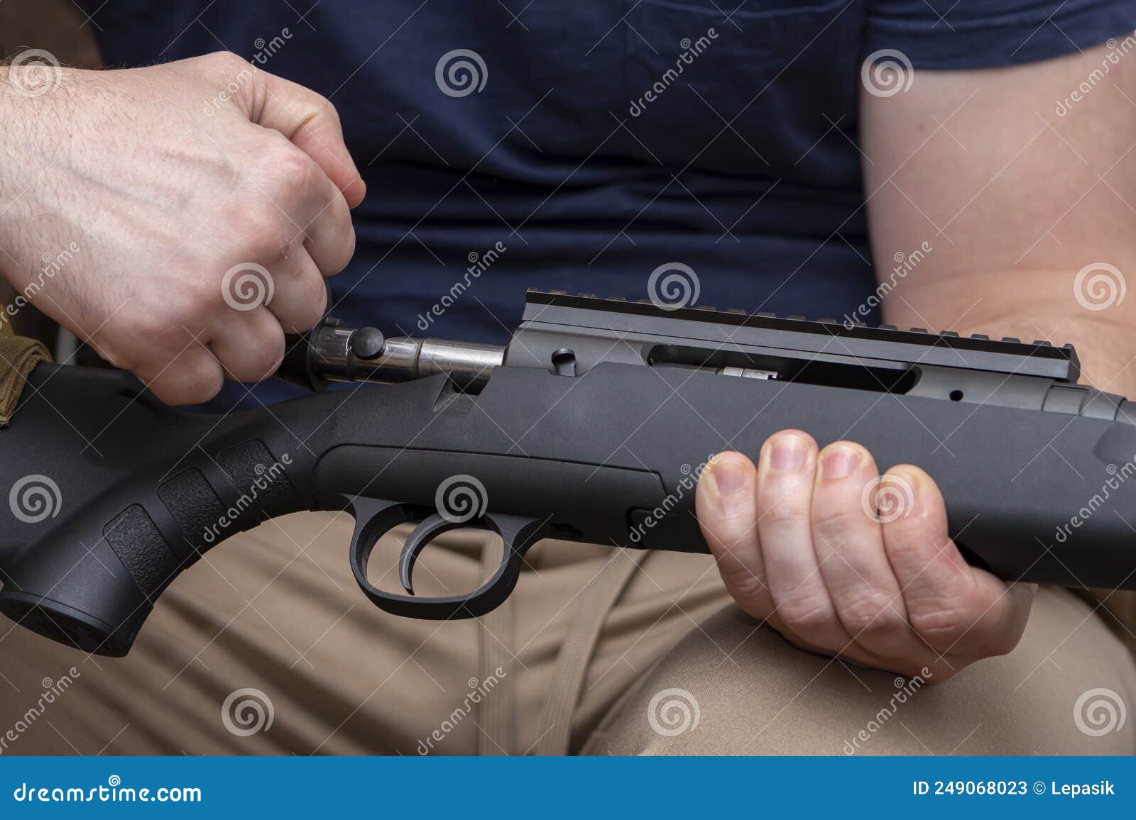 A Man Holds A Rifle On His Knees, Pulls Back The Bolt, Reloads The ...