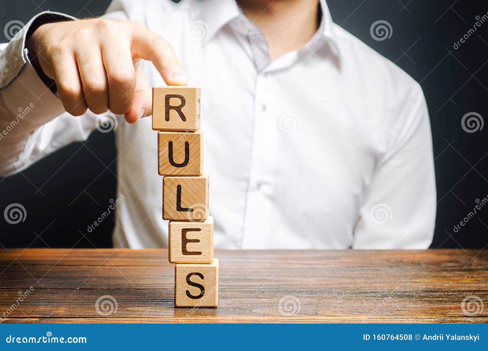 A Man Holds a Tower of Blocks with the Word Rules from Falling. Setting ...
