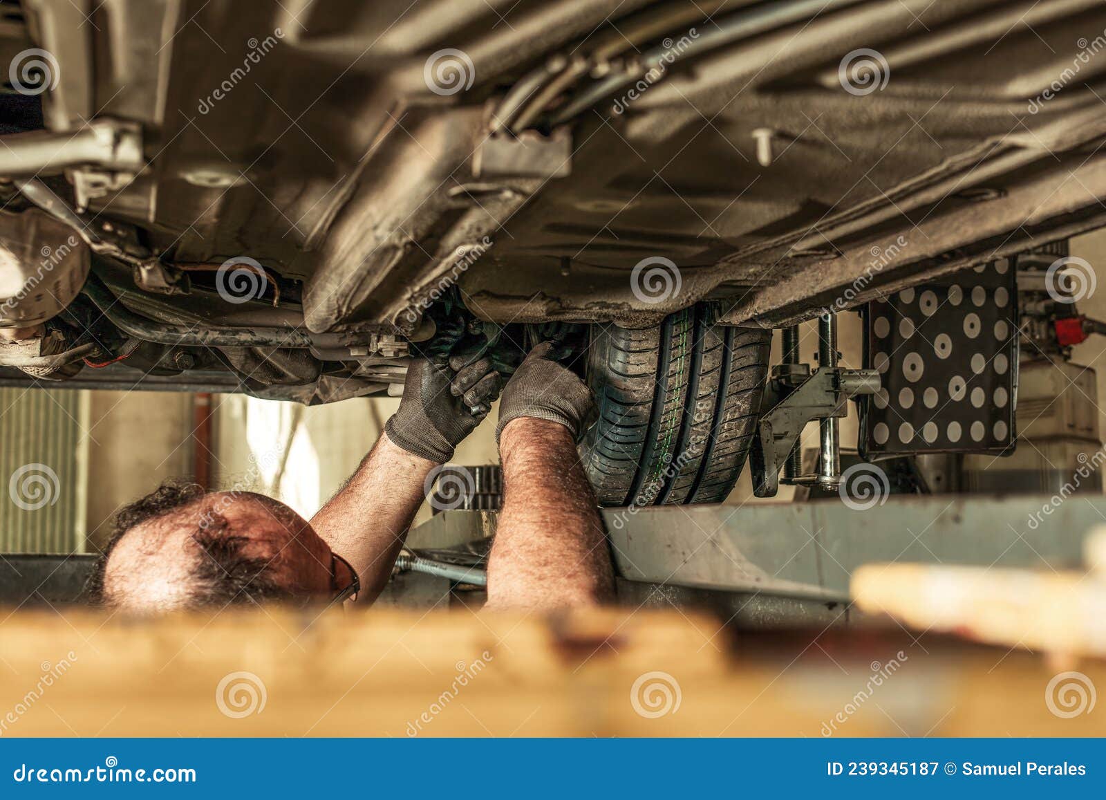 Man in a Hole Under a Car Fixing Steering Alignment in a Garage Stock ...
