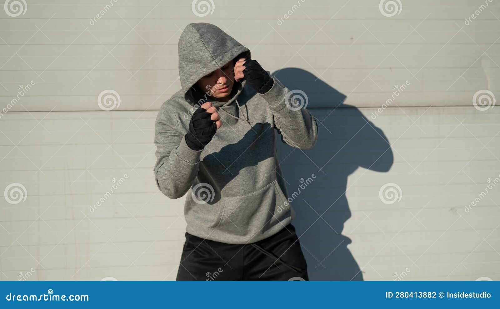 A Man in a Hoody Trains Boxing Against a Gray Wall. Stock Photo - Image ...