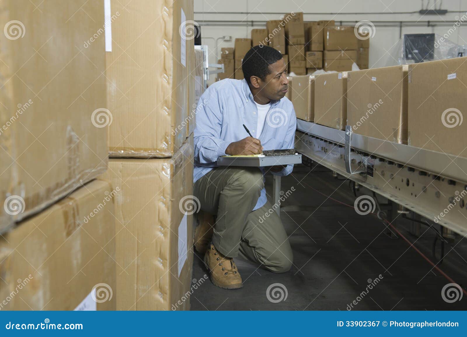 Man Inspecting Boxes on Conveyor Belt Stock Image - Image of crouching ...