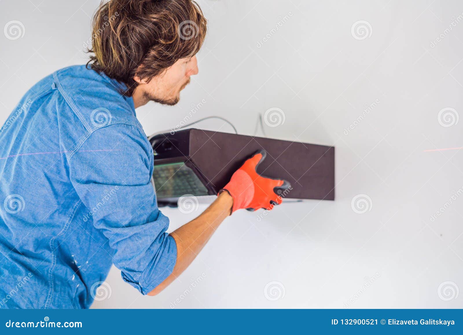 A Man is Installing an Electrical Device on a Wall in a New Apartment ...