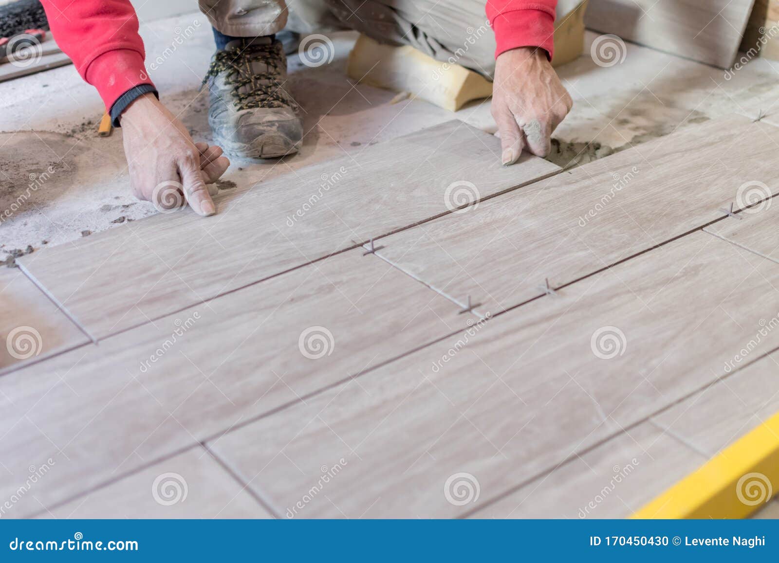 Man Installing Rectangular Shaped Floor Tiles in Kitchen. Applying Adhesive before Installation ...