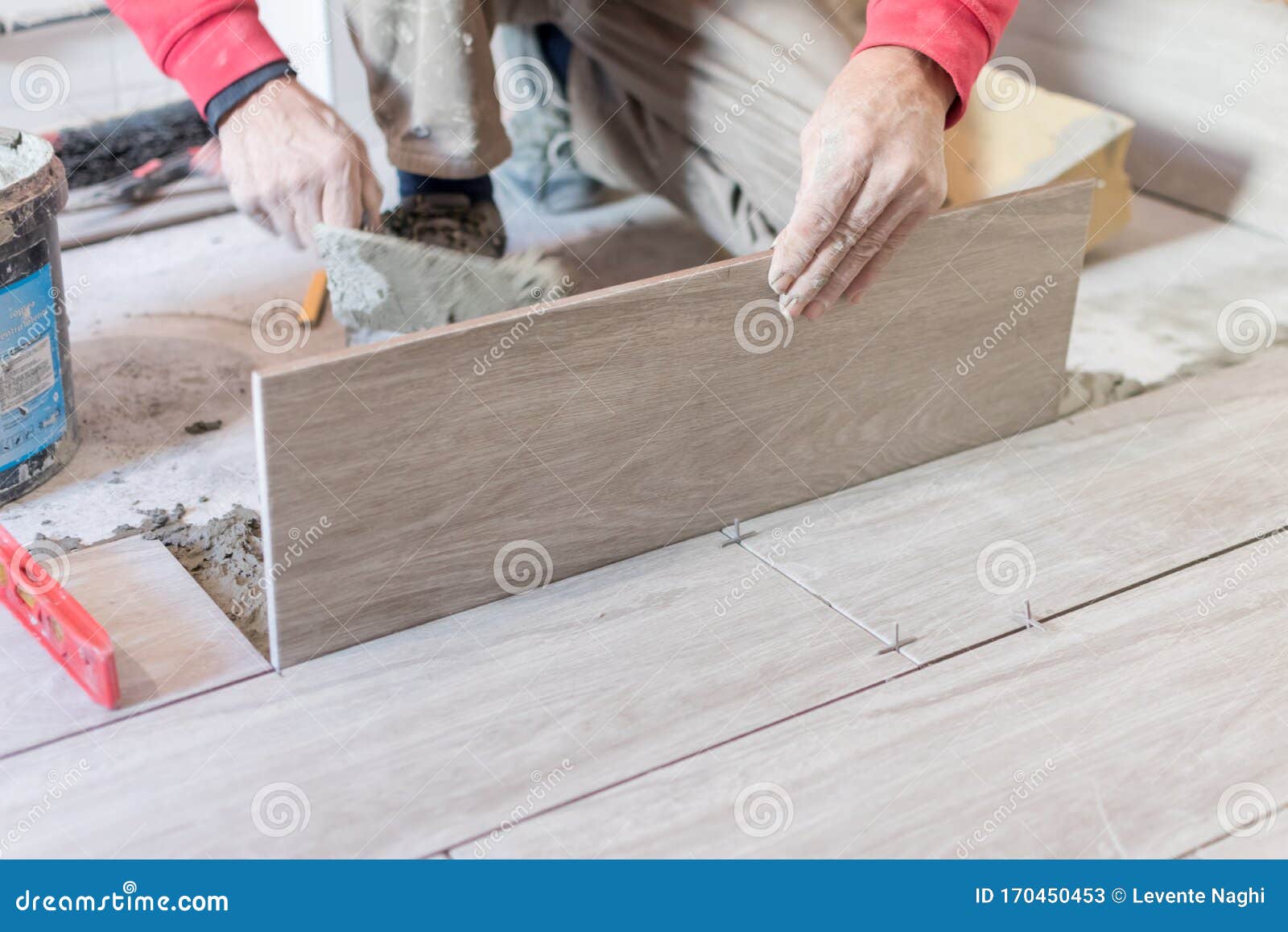 Man Installing Rectangular Shaped Floor Tiles in Kitchen. Applying Adhesive before Installation ...