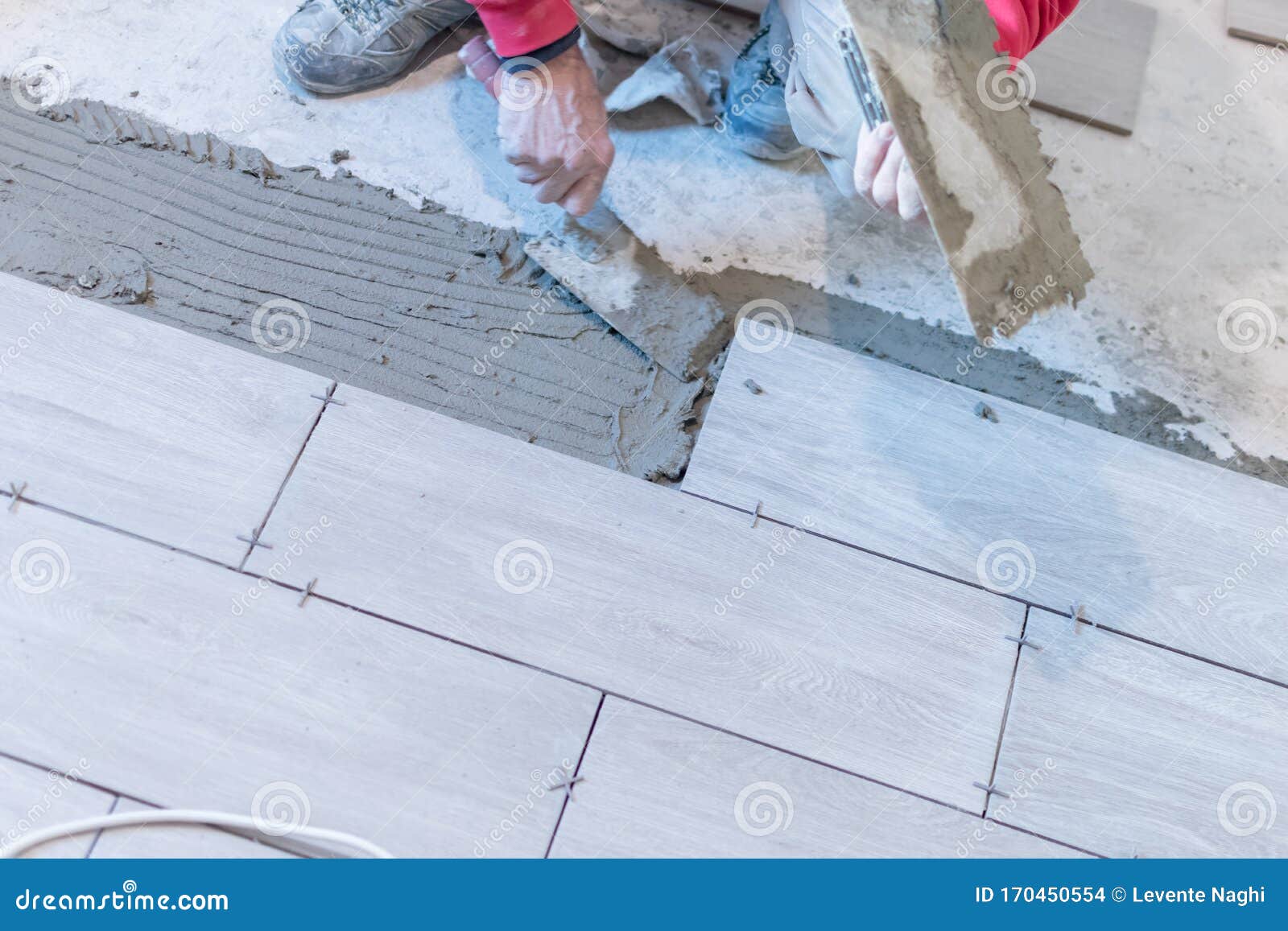 Man Installing Rectangular Shaped Floor Tiles in Kitchen. Applying Adhesive before Installation ...