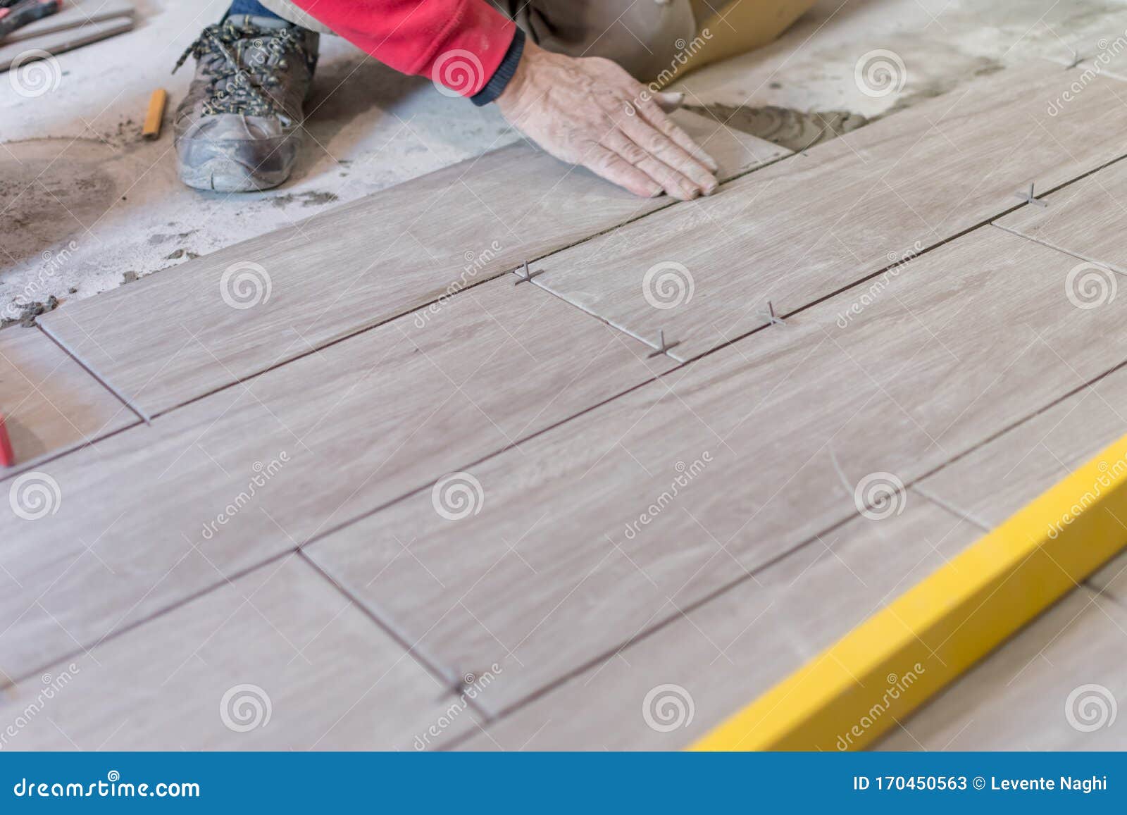 Man Installing Rectangular Shaped Floor Tiles in Kitchen. Applying ...