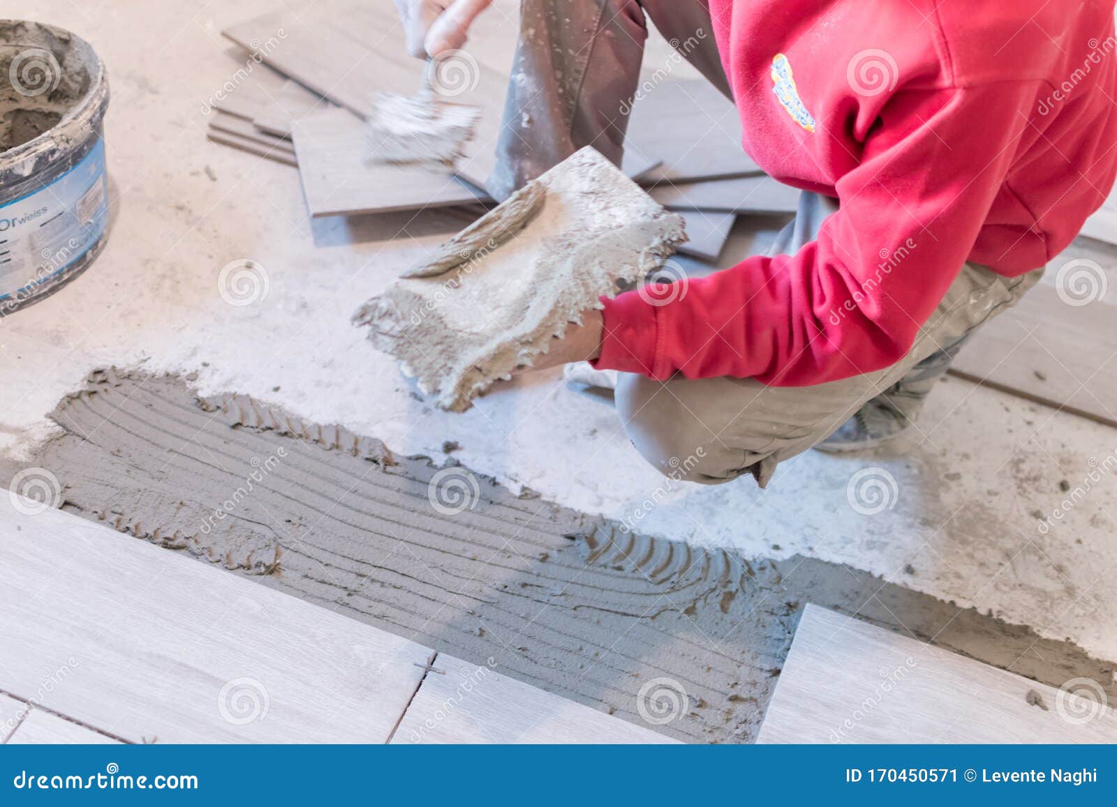Man Installing Rectangular Shaped Floor Tiles in Kitchen. Applying Adhesive before Installation ...
