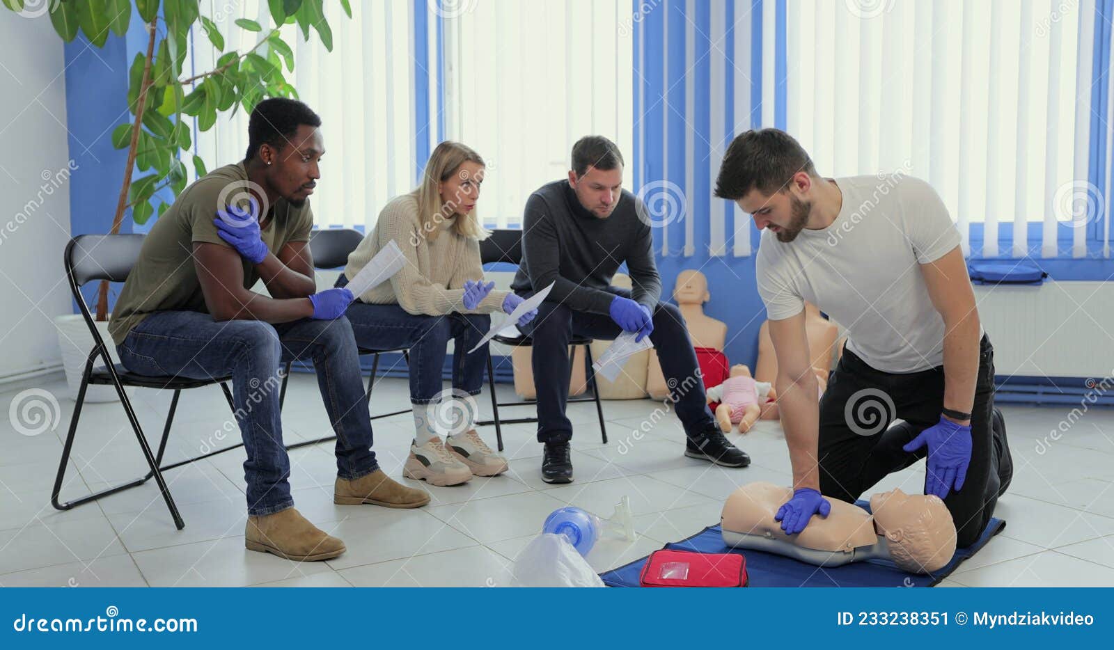 Man Instructor Showing How To Make Chest Compressions with Dummy during ...