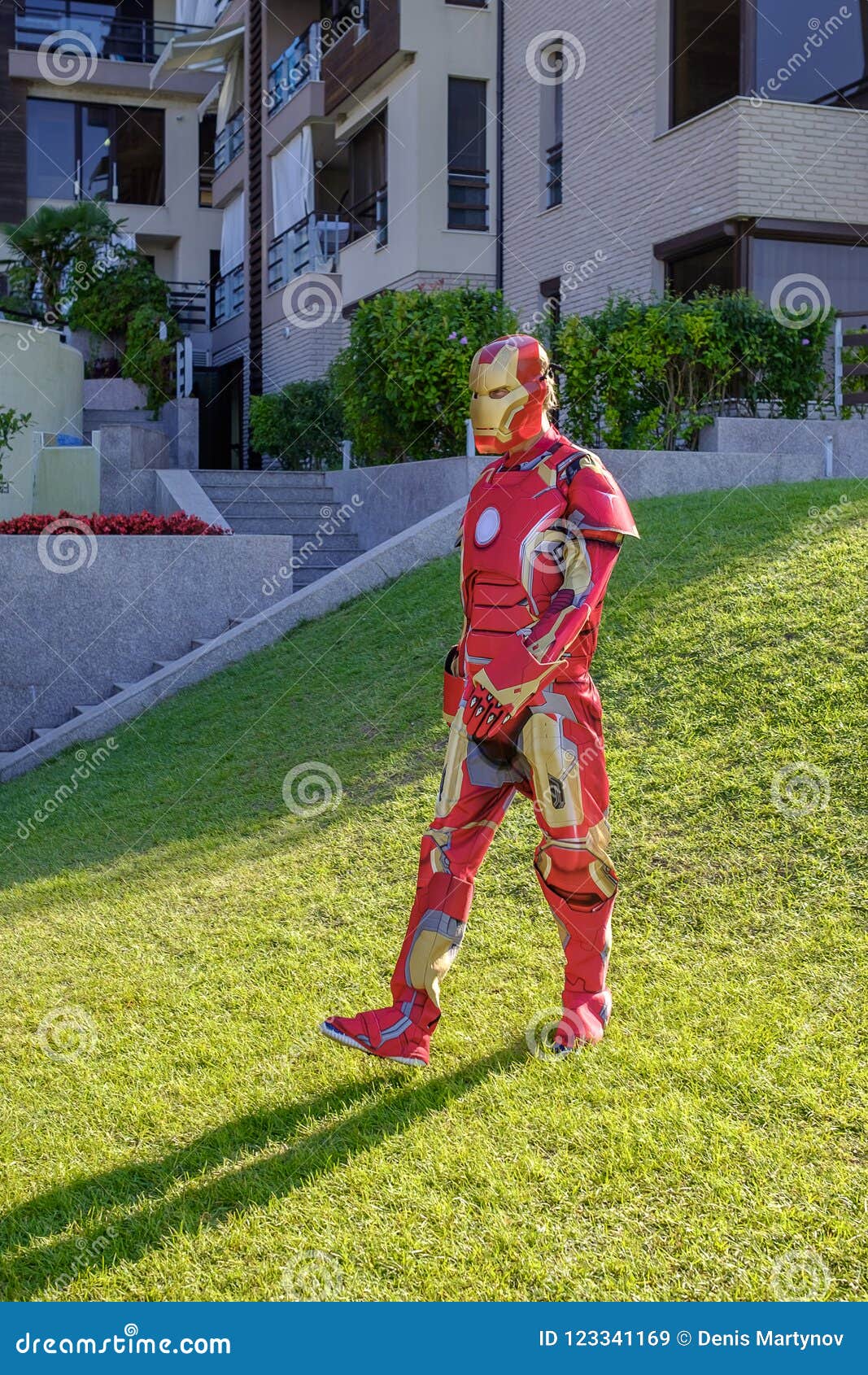 An Iron Man Walks Along the Green Grass in the Glade Editorial Stock ...