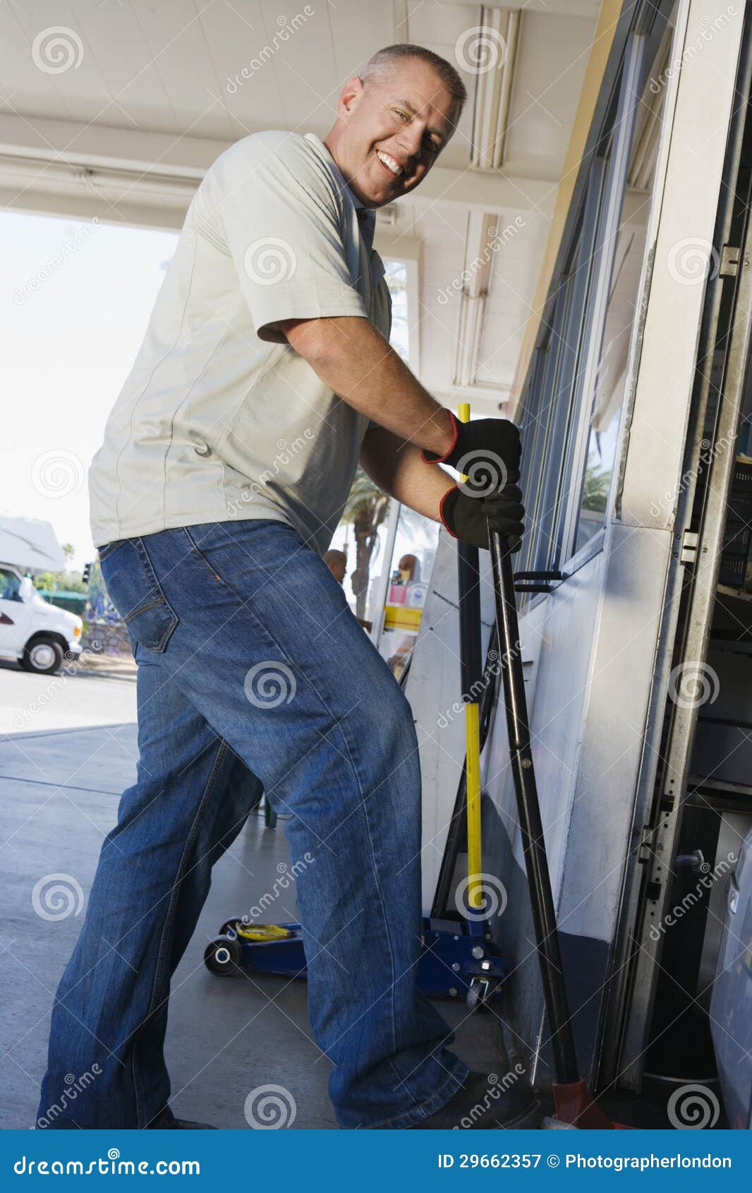 Man Jacking Up Vehicle in Service Station Stock Image - Image of ...