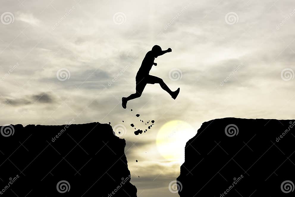 Man Jumping Across a Gap between the Cliffs in the Mountains Stock ...