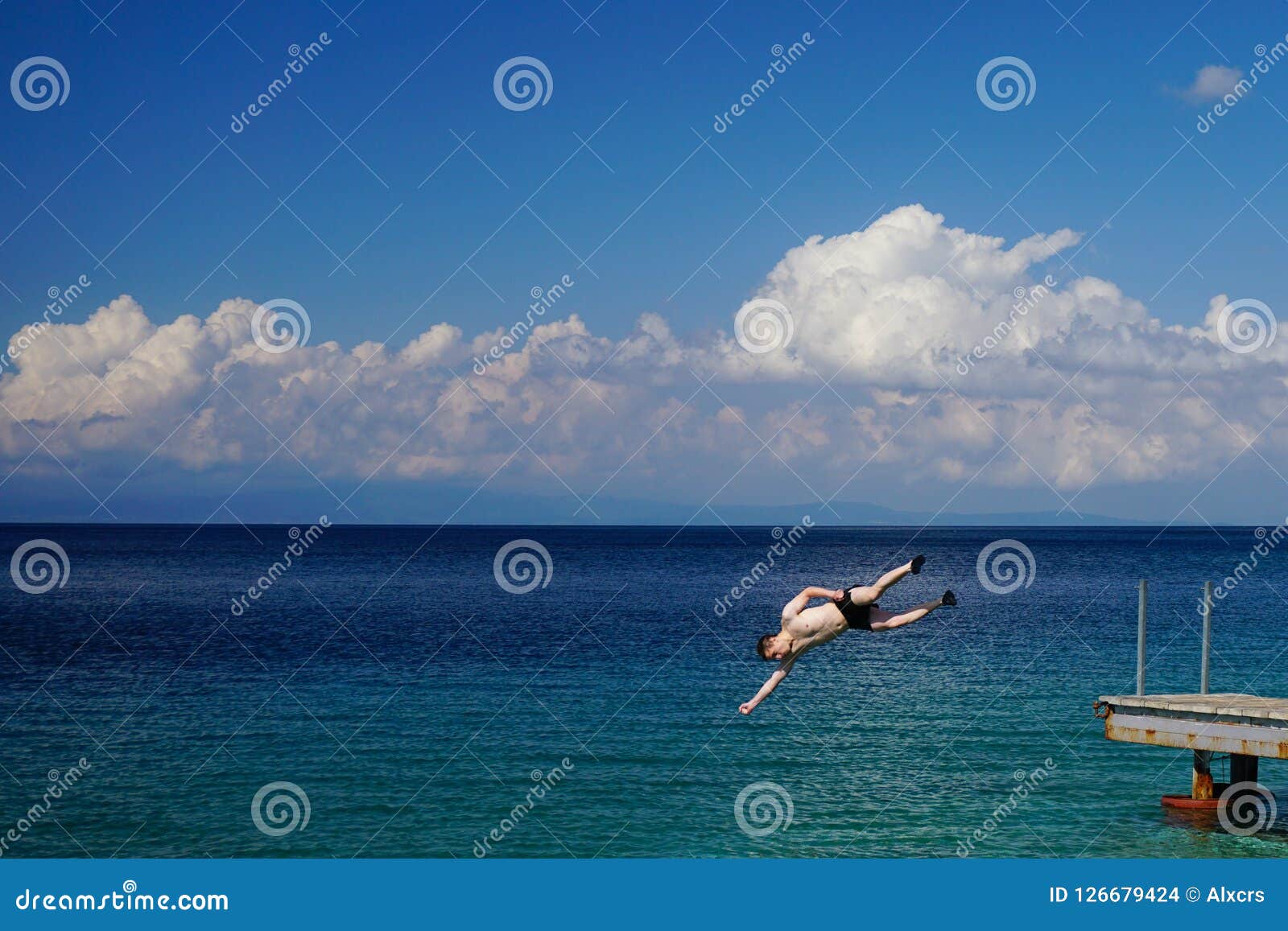 Man Jumping in Sea from Pier Stock Photo - Image of jumping, clouds ...