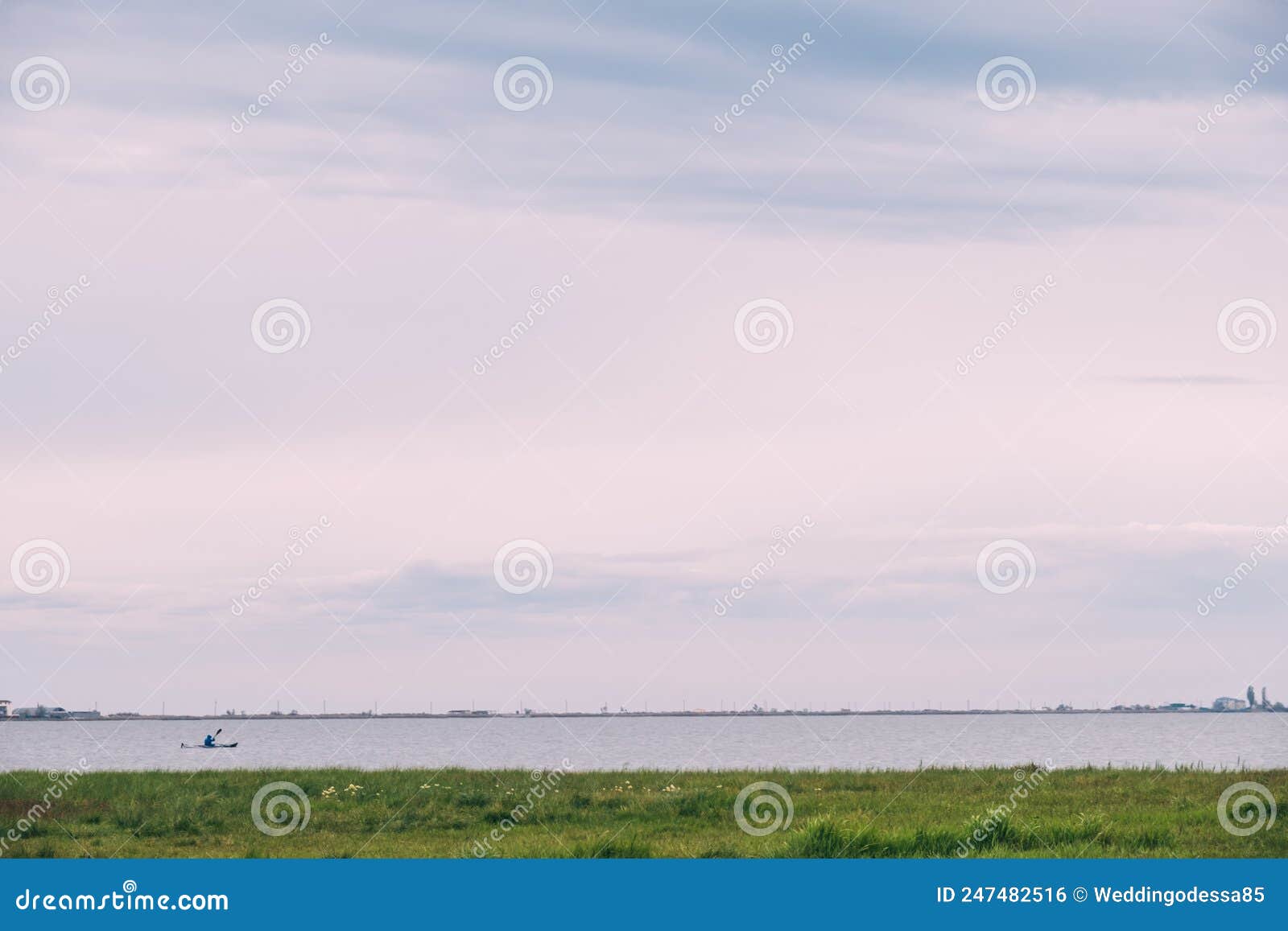A Man on a Kayak in the Distance on the Horizon between Two Shores ...