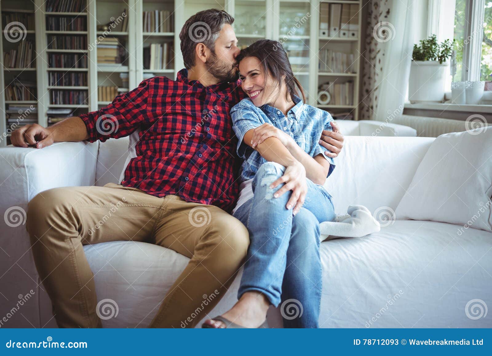 Man Kissing Woman While Sitting On Sofa In Living Room Stock Image