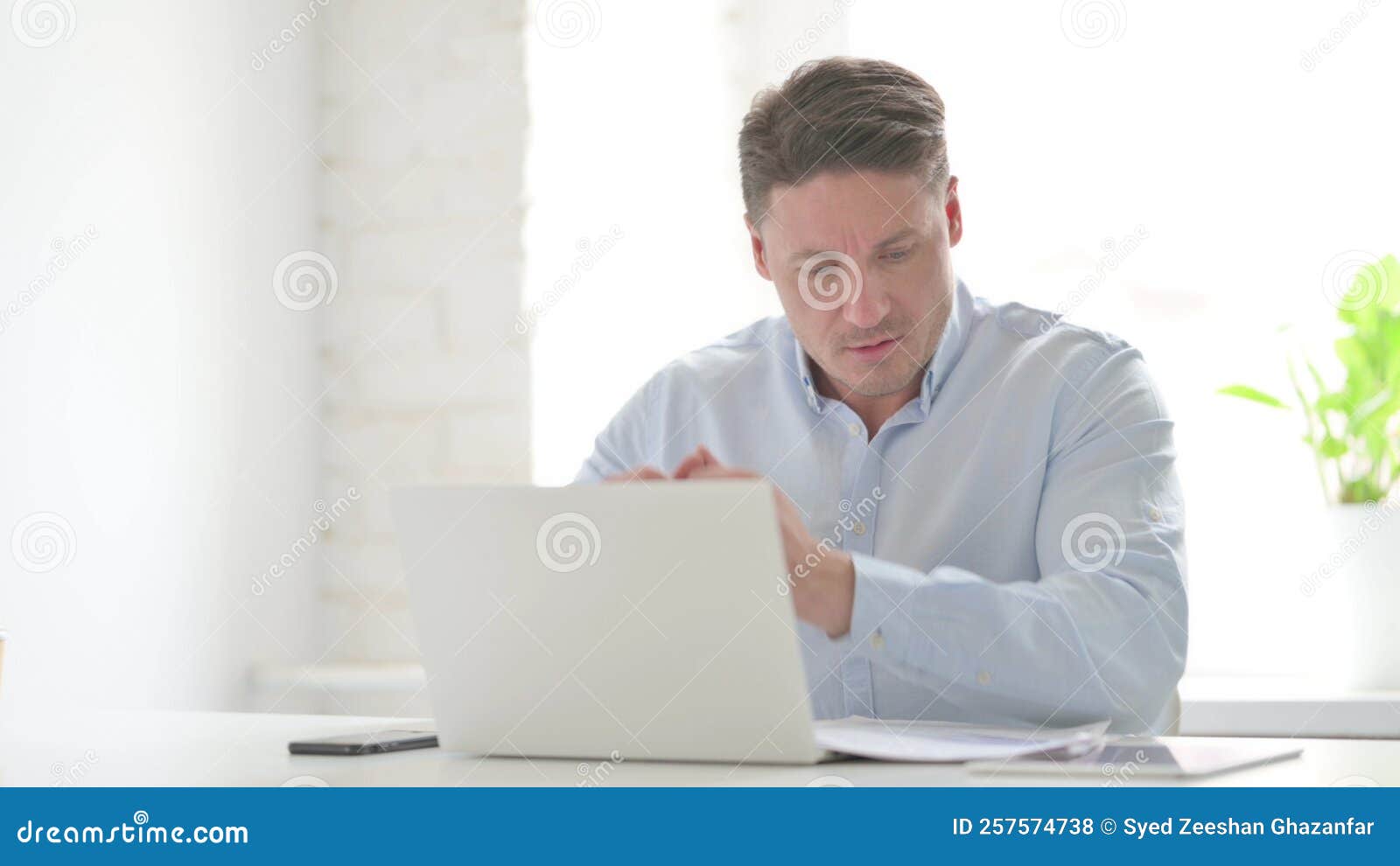 Man with Laptop Having Loss while Reading Documents Stock Photo - Image ...
