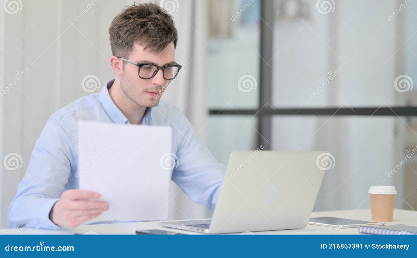 Man with Laptop Reading Documents in Office Stock Image - Image of ...